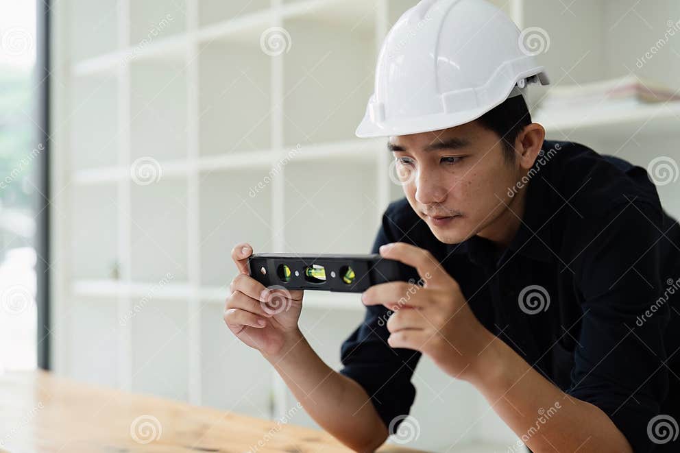 Focused Construction Worker Using a Level Tool for Precision Measurement in Modern Office ...