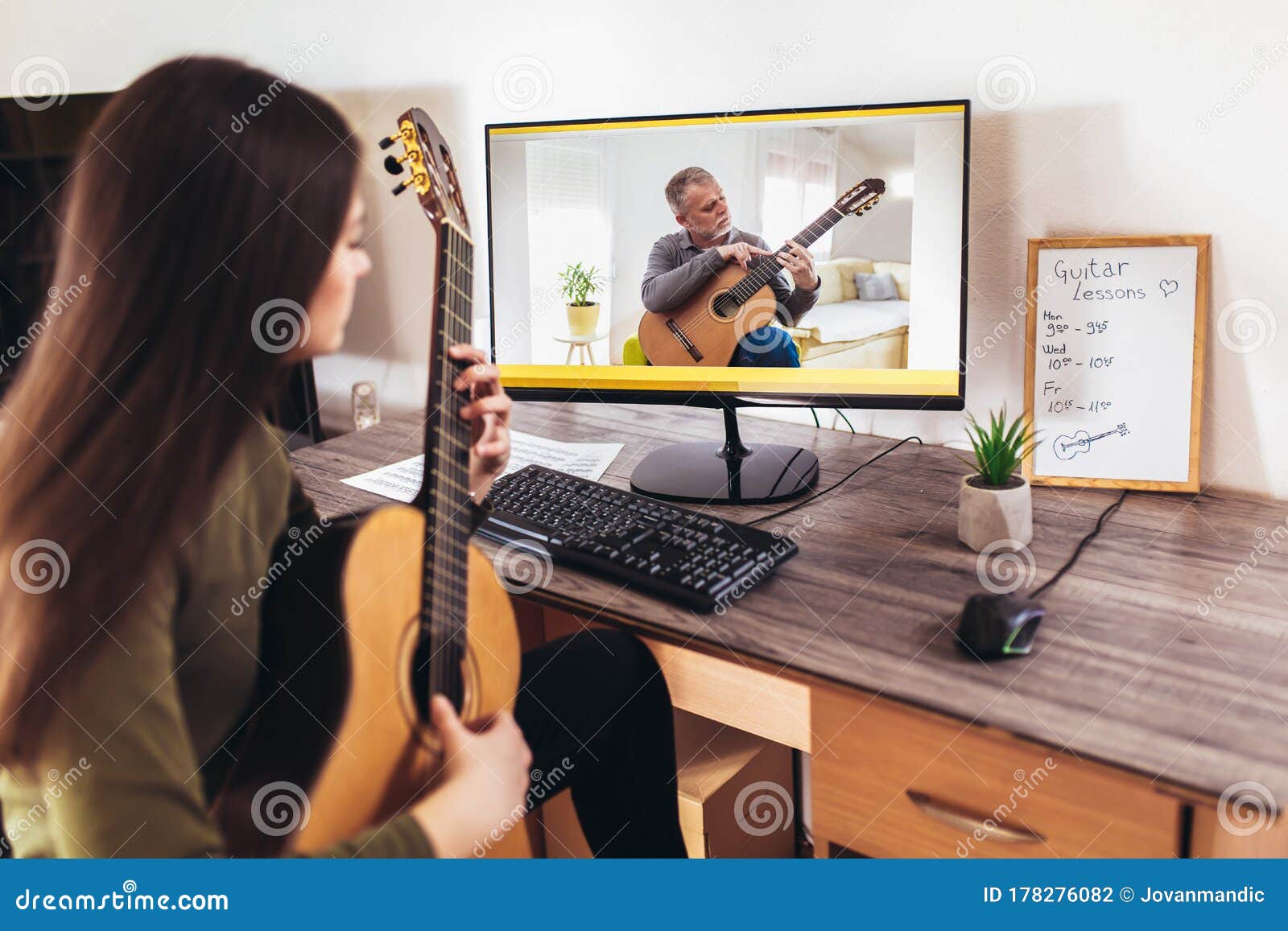 Girl Playing Acoustic Guitar and Watching Online Course on Laptop while ...