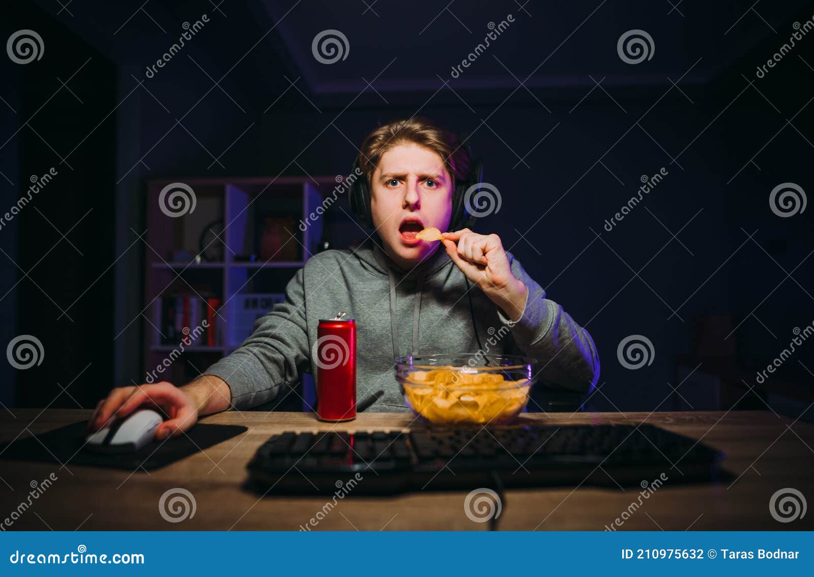 Focused Guy Looks at the Computer Screen at Night and Eats Snacks ...