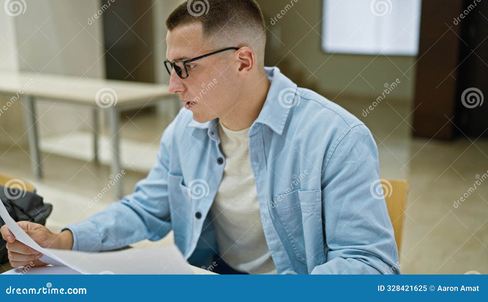 A Focused Hispanic Man Studying Documents at a University Library ...