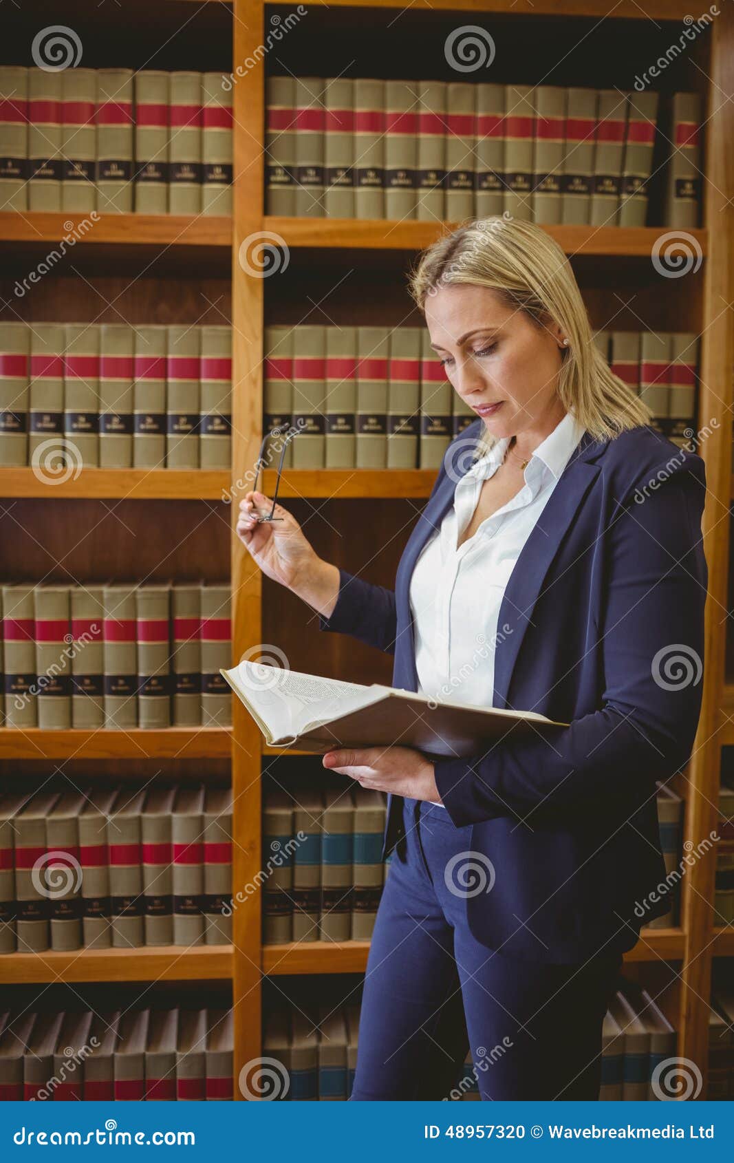 Focused Librarian Reading Book and Holding Reading Glasses Stock Photo ...