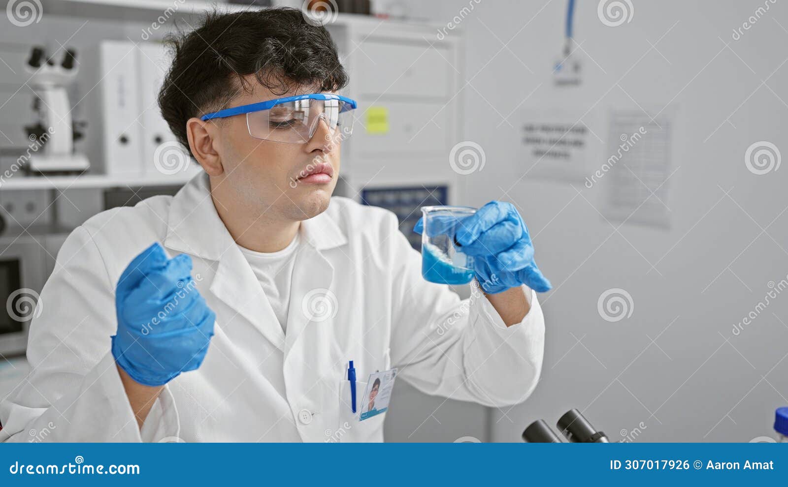 Focused Man in Lab Coat Analyzing Blue Chemical in Beaker at Indoor ...