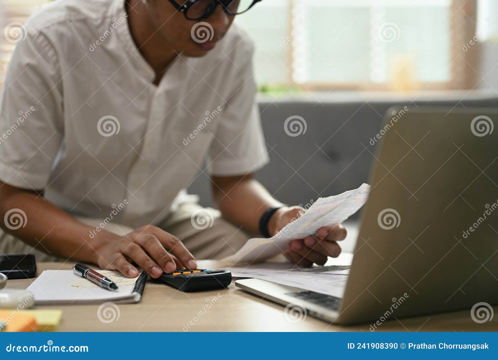 Focused Man Look at Laptop Screen and Using Calculator for Calculating ...