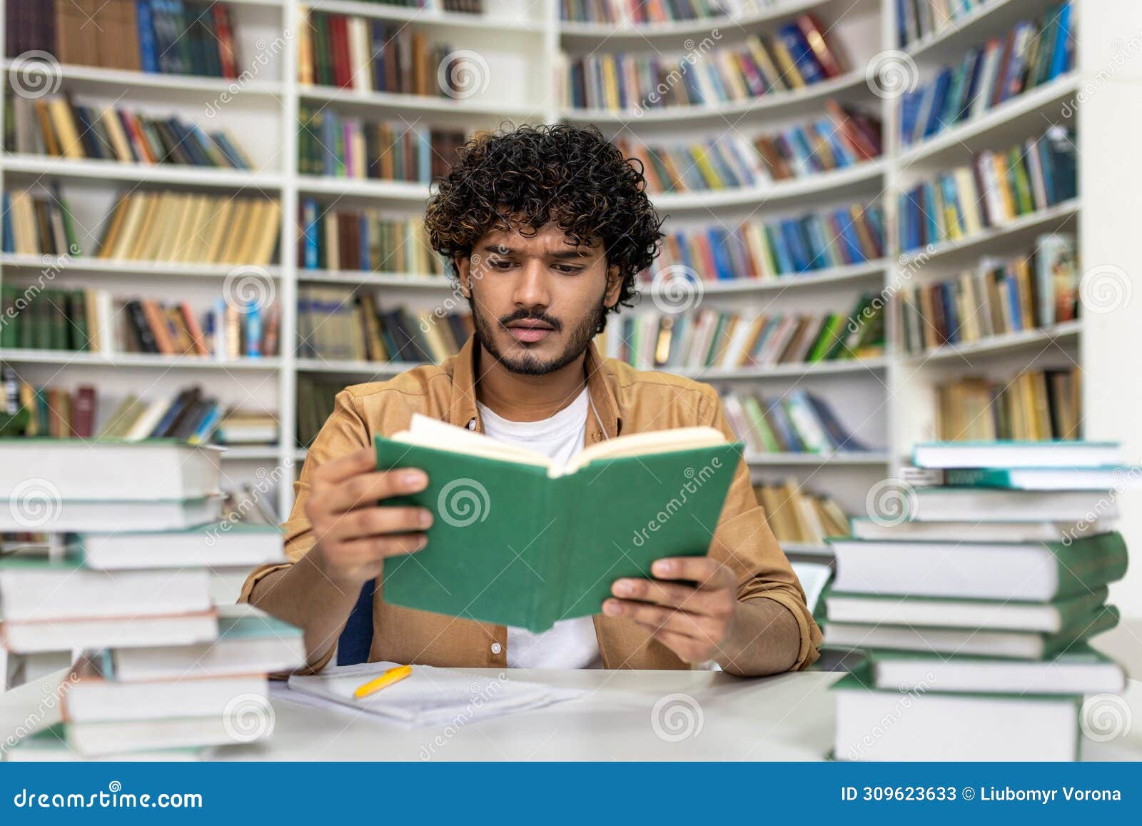 Focused Student Studying in Library Surrounded by Stacks of Books Stock ...