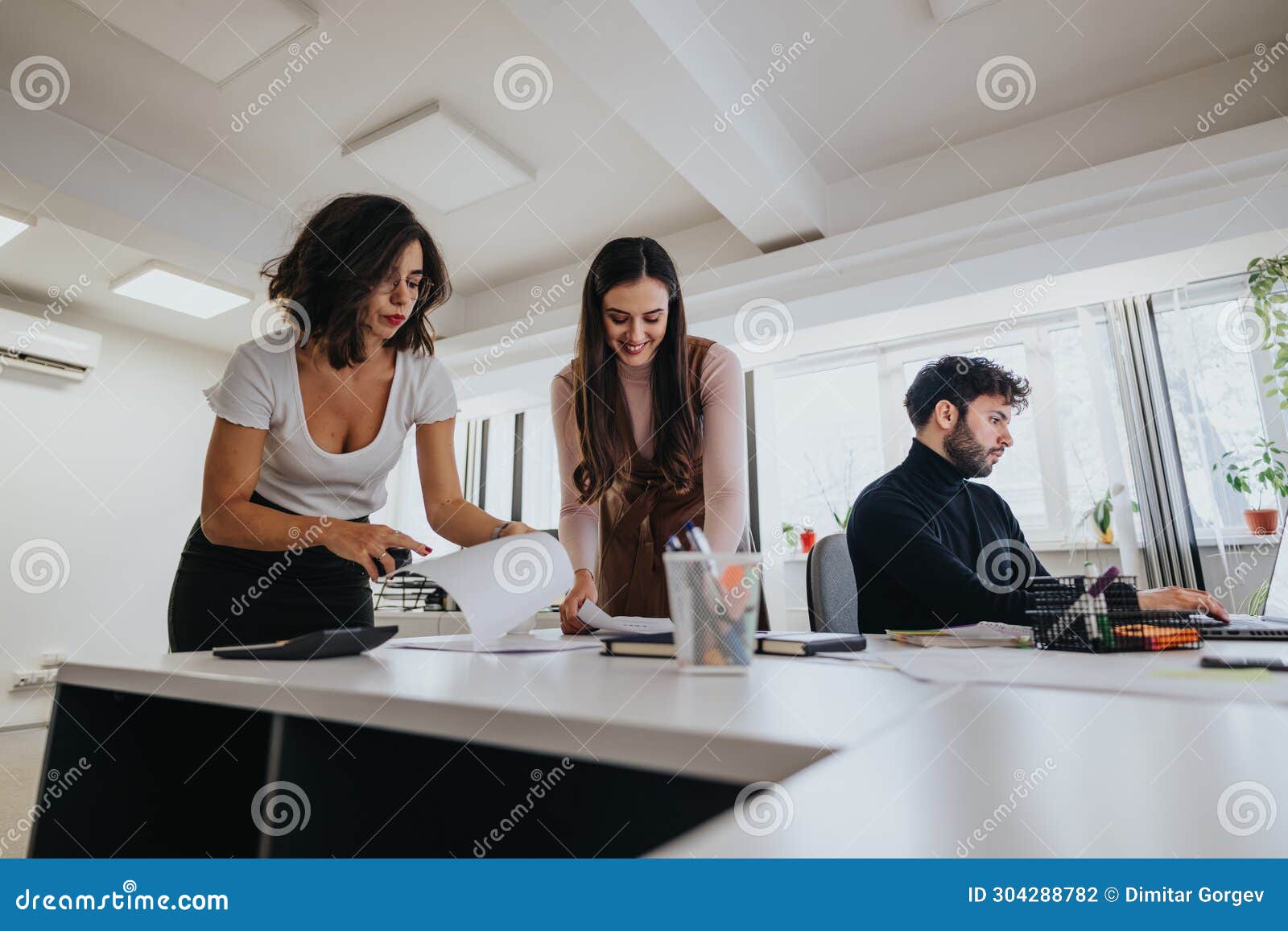 Focused Team at Work in a Modern Office: Two Women Collaborating and a ...