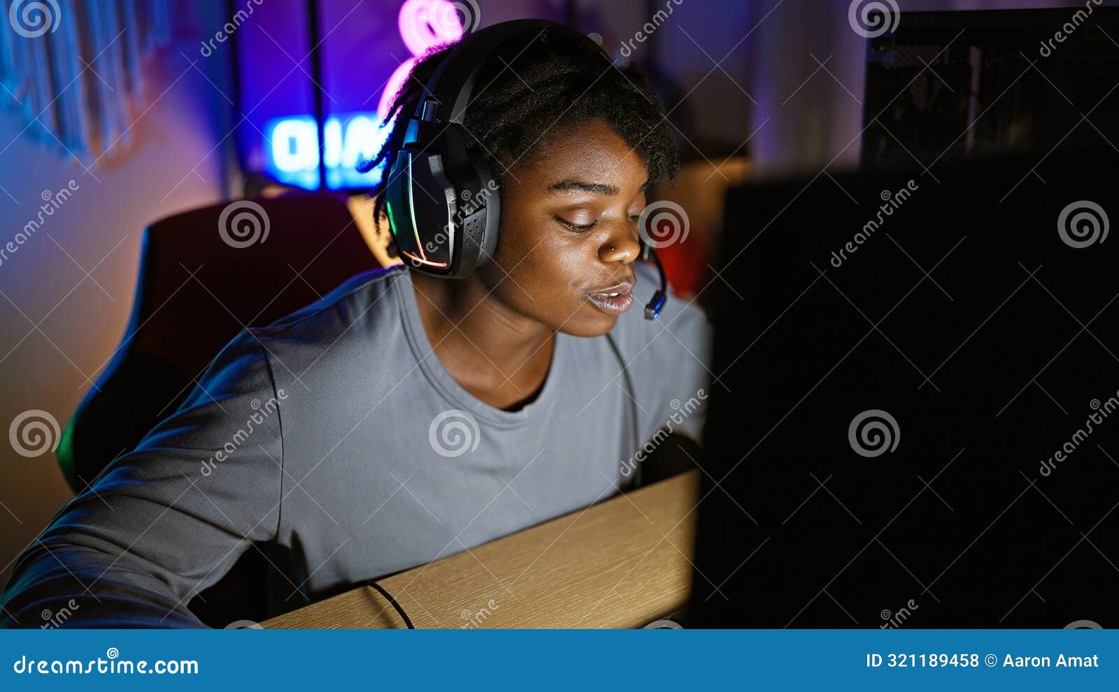 Focused Woman Wearing Headphones Using Computer in a Gaming Room at ...