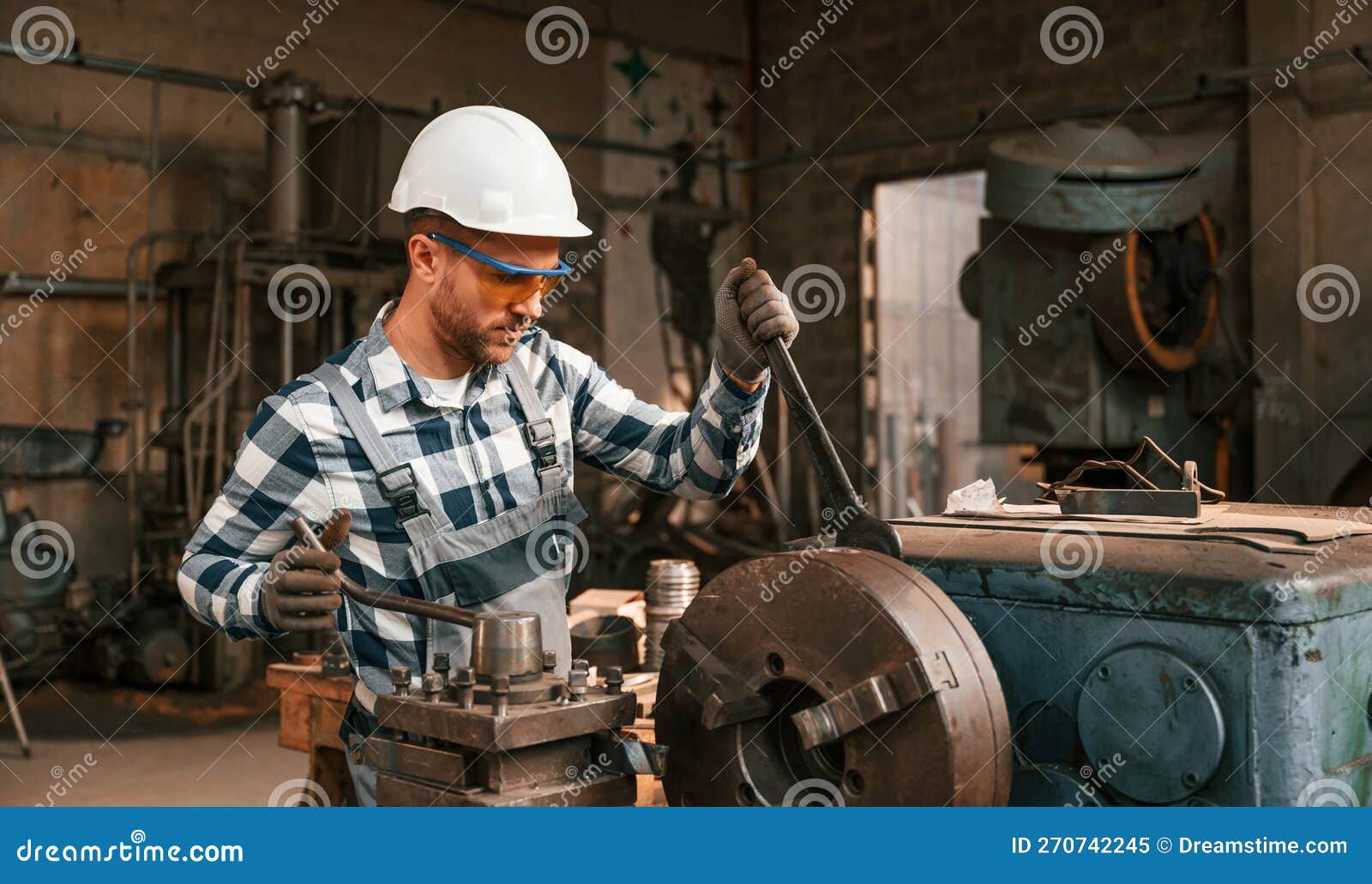 Focused on Work with Factory Machine. Worker in Uniform is Indoors ...