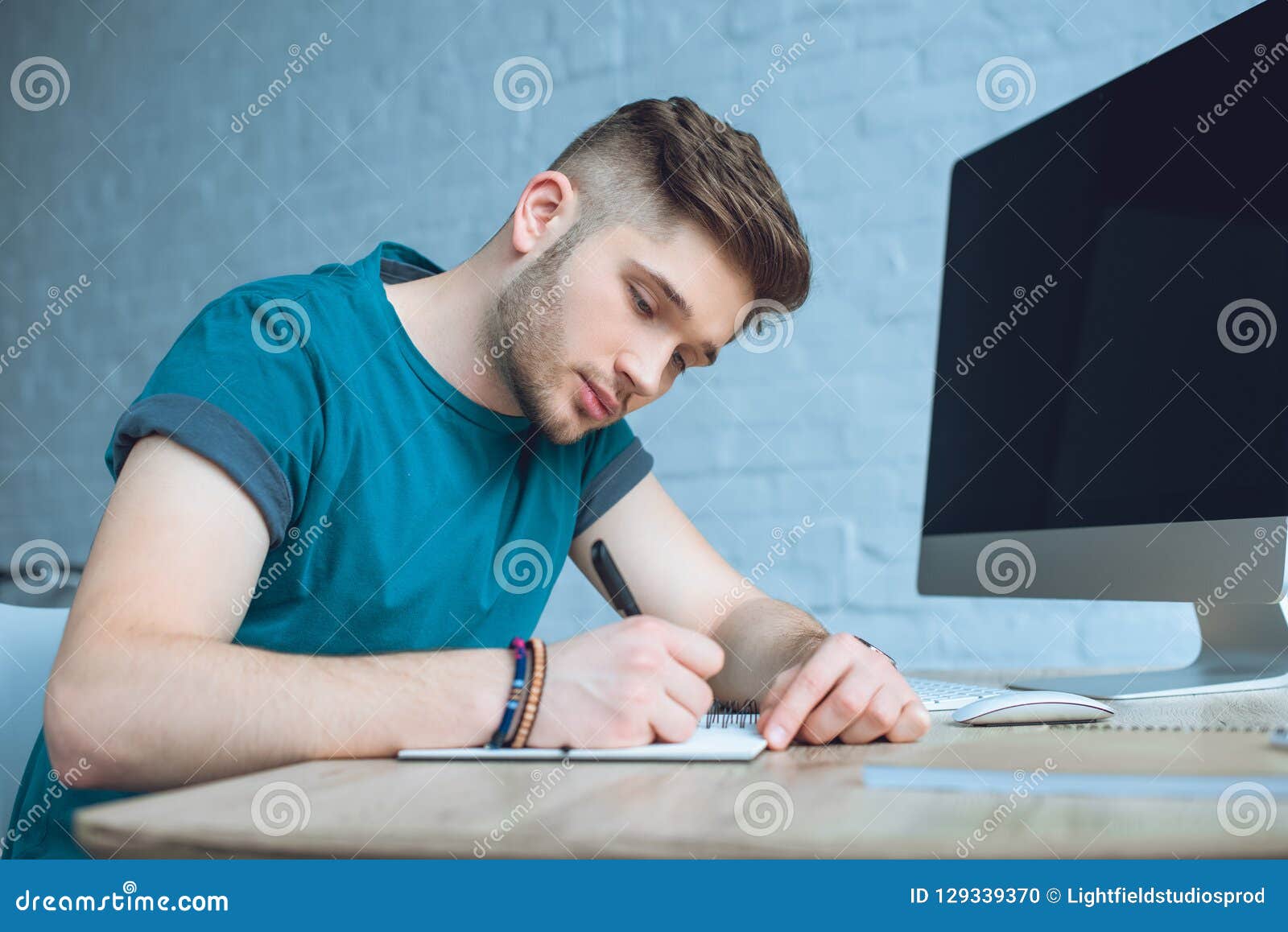 Focused Young Man Writing in Notebook while Working Stock Photo - Image ...