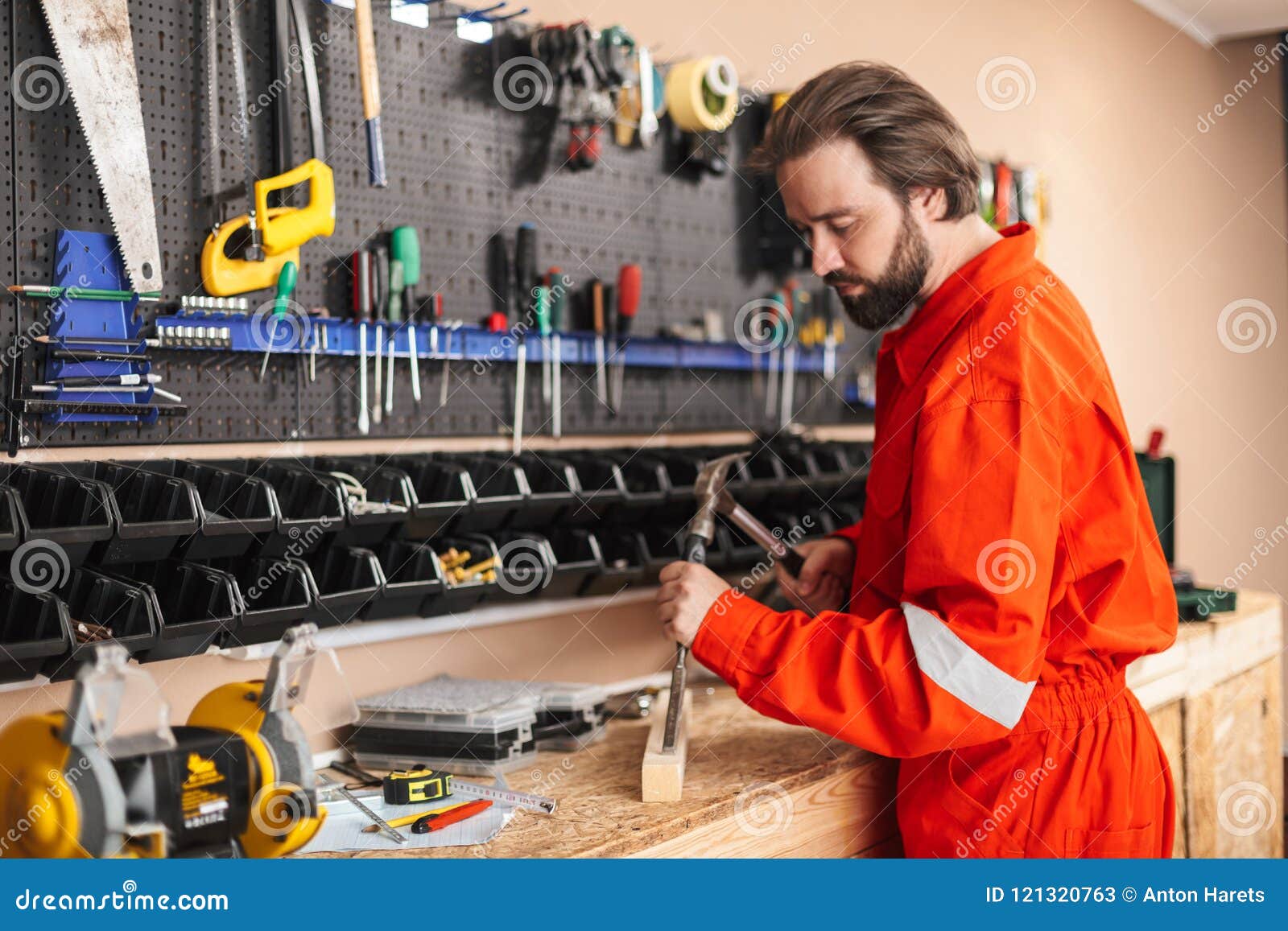 Foreman in Work Clothes Thoughtfully Using Hammer with Stand of Stock ...
