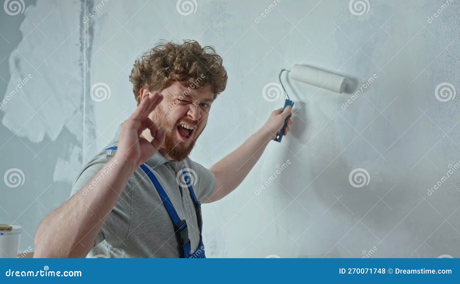 Foreman or Painter in Blue Construction Overalls is Painting Wall with ...