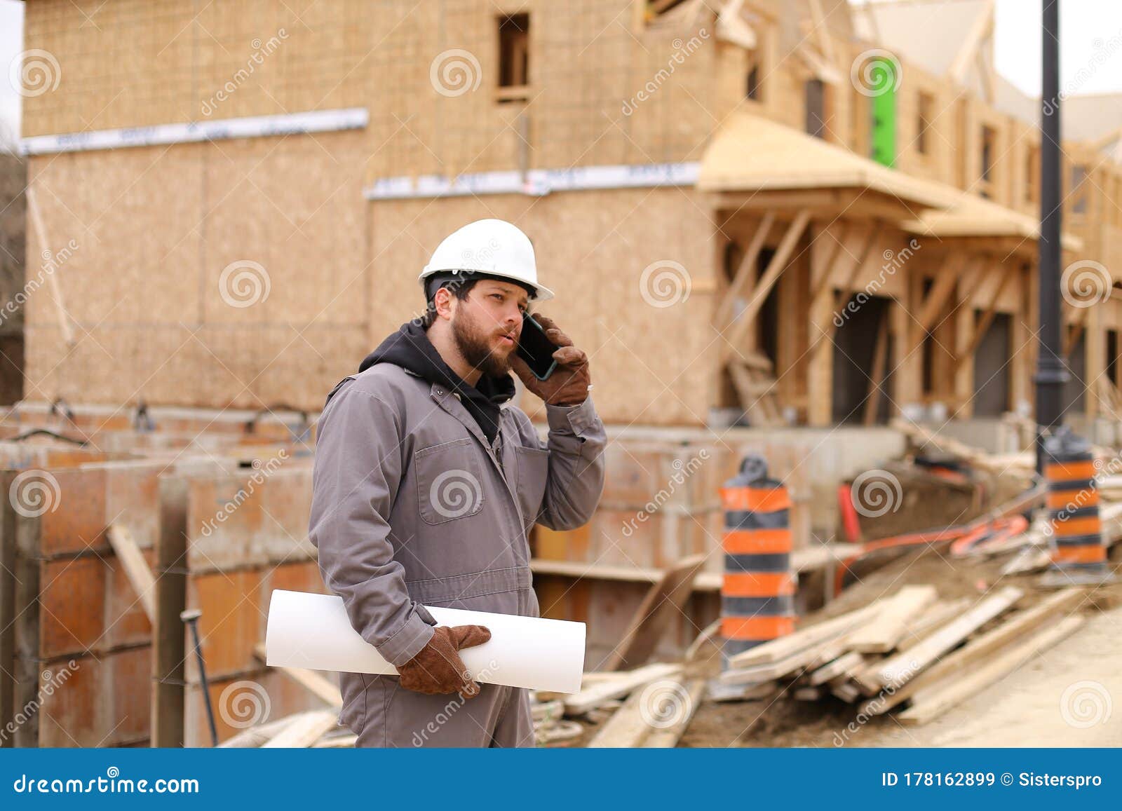 Foreman Talking by Smartphone and Holding Drawing Plan at Construction ...