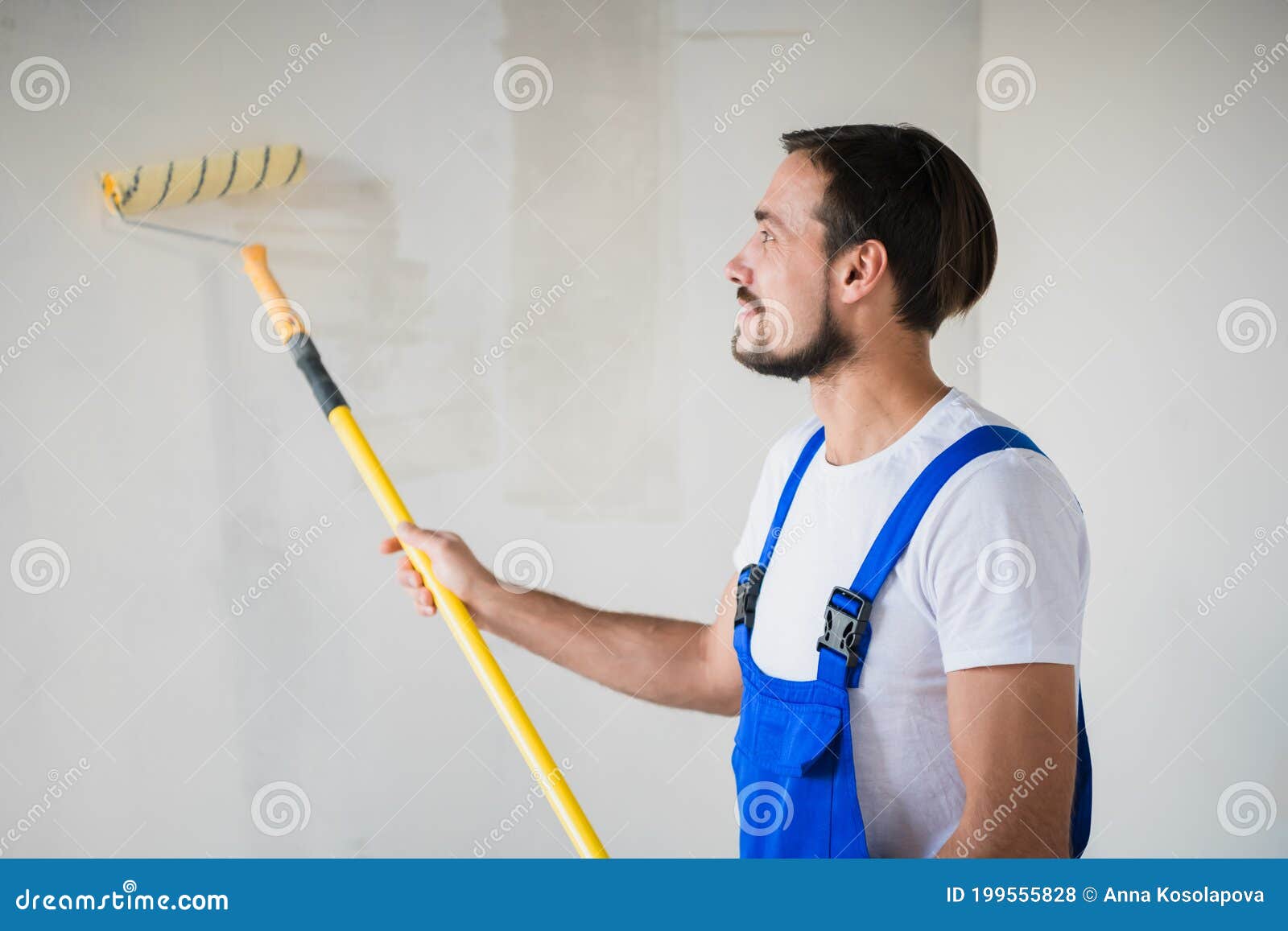 Foreman in Work Clothes Paints the Wall White with a Roller Stock Photo ...