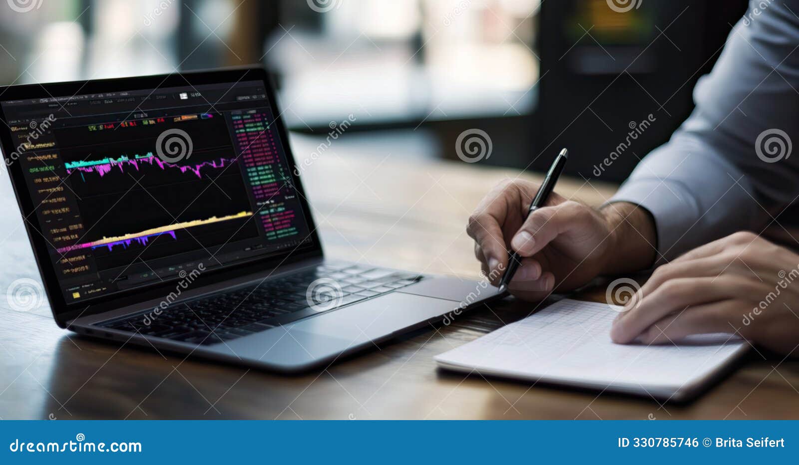 A Forex Trading Expert Writing Notes on a Paper Pad Next To a Running ...