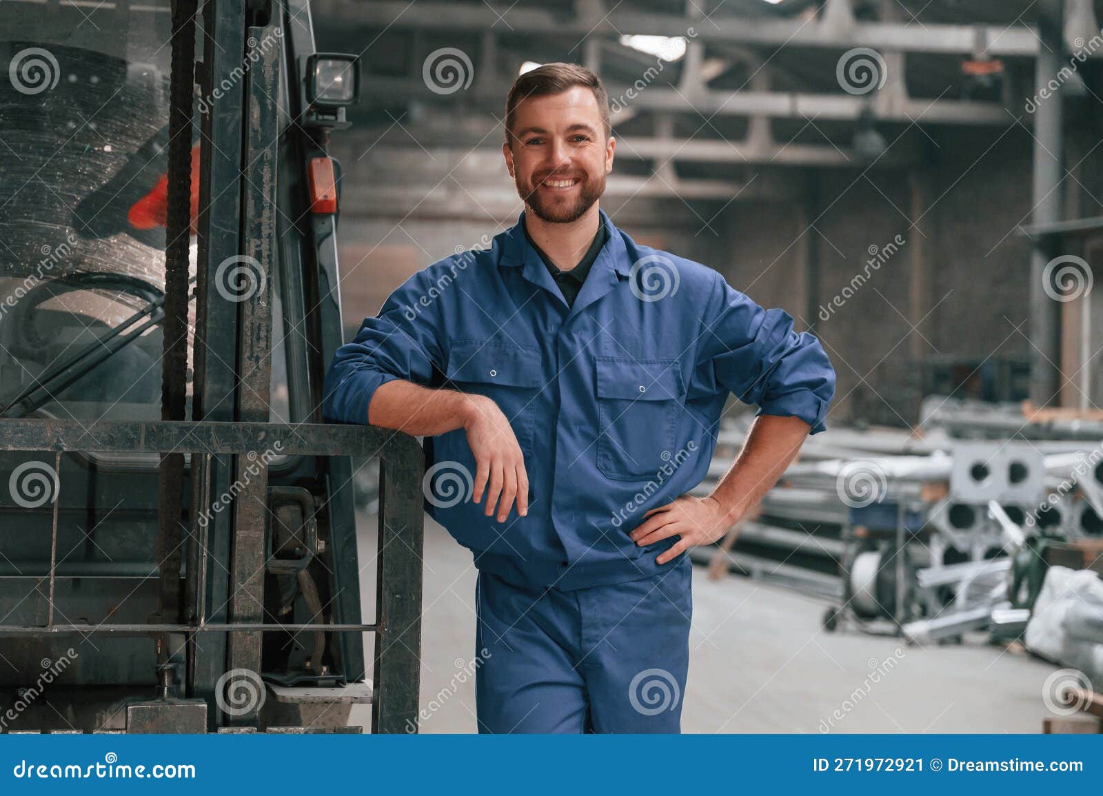 With the Forklift. Factory Worker in Blue Uniform is Indoors Stock ...