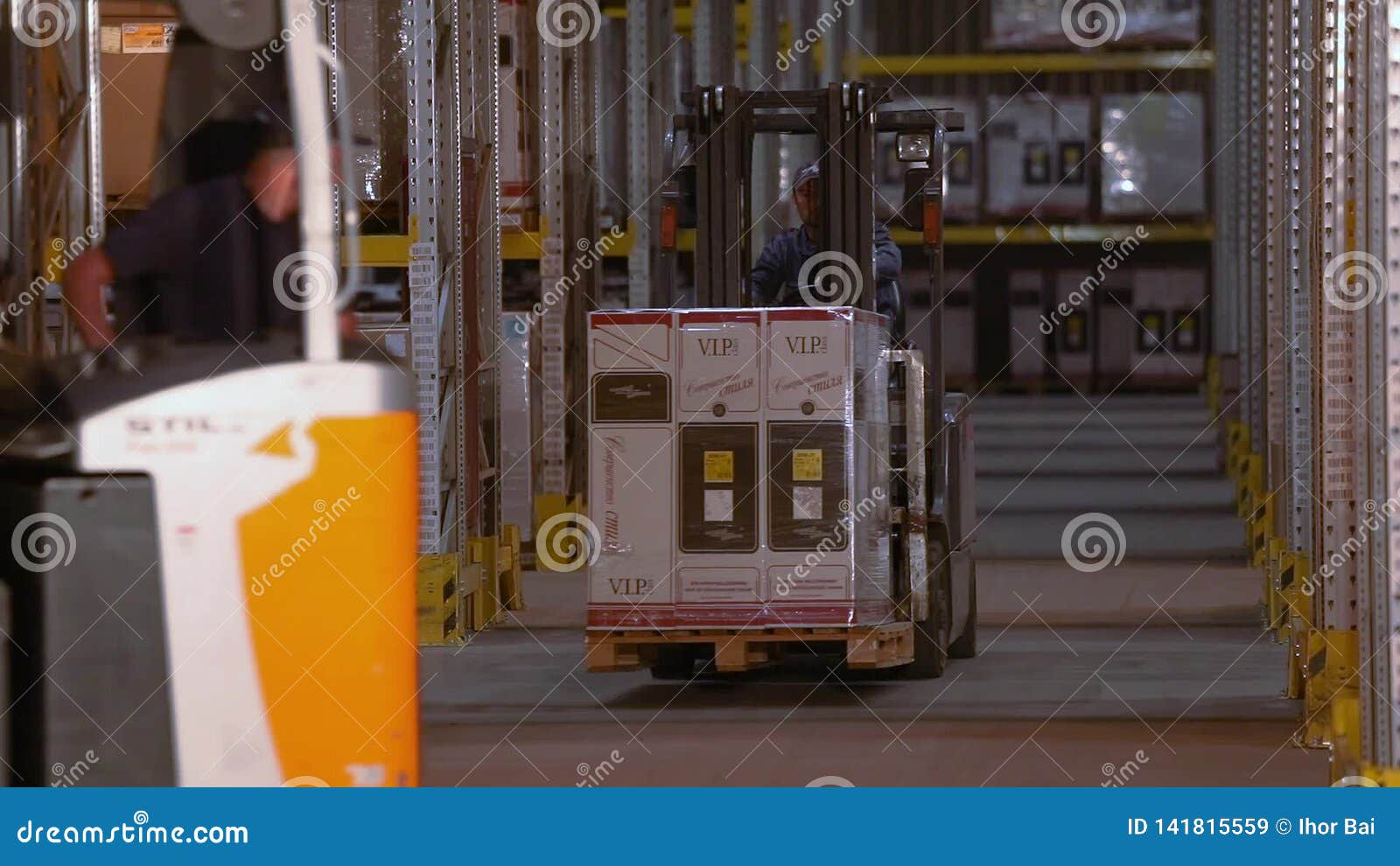 Forklift Rides between Rows in a Warehouse, a Man Drives a Forklift in ...