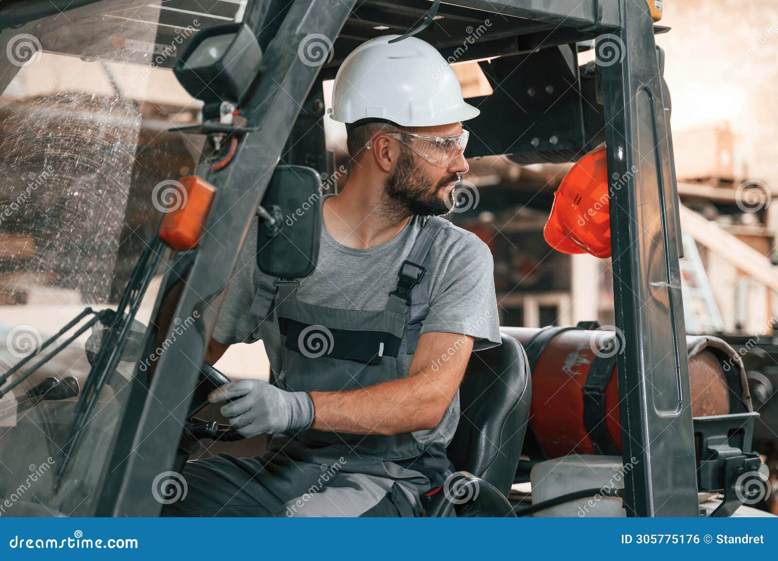 In the Forklift. Young Factory Worker in Grey Uniform Stock Photo ...