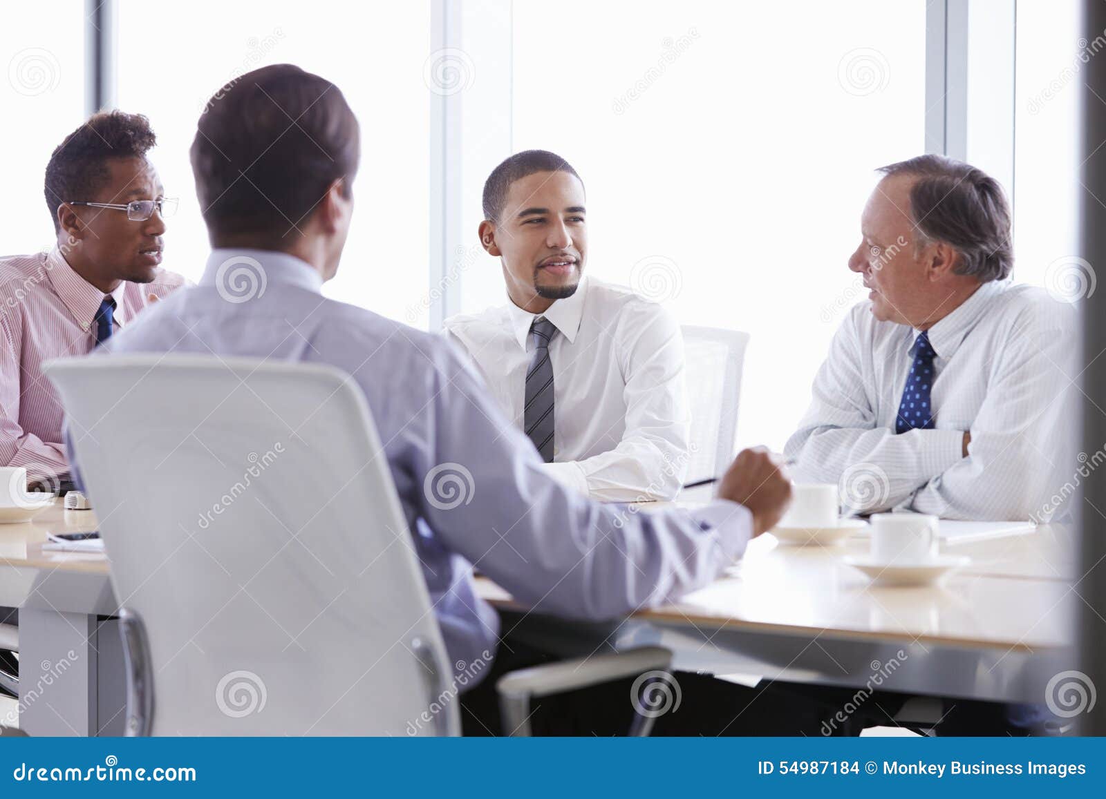 Four Businessmen Having Meeting Around Boardroom Table Stock Photo ...