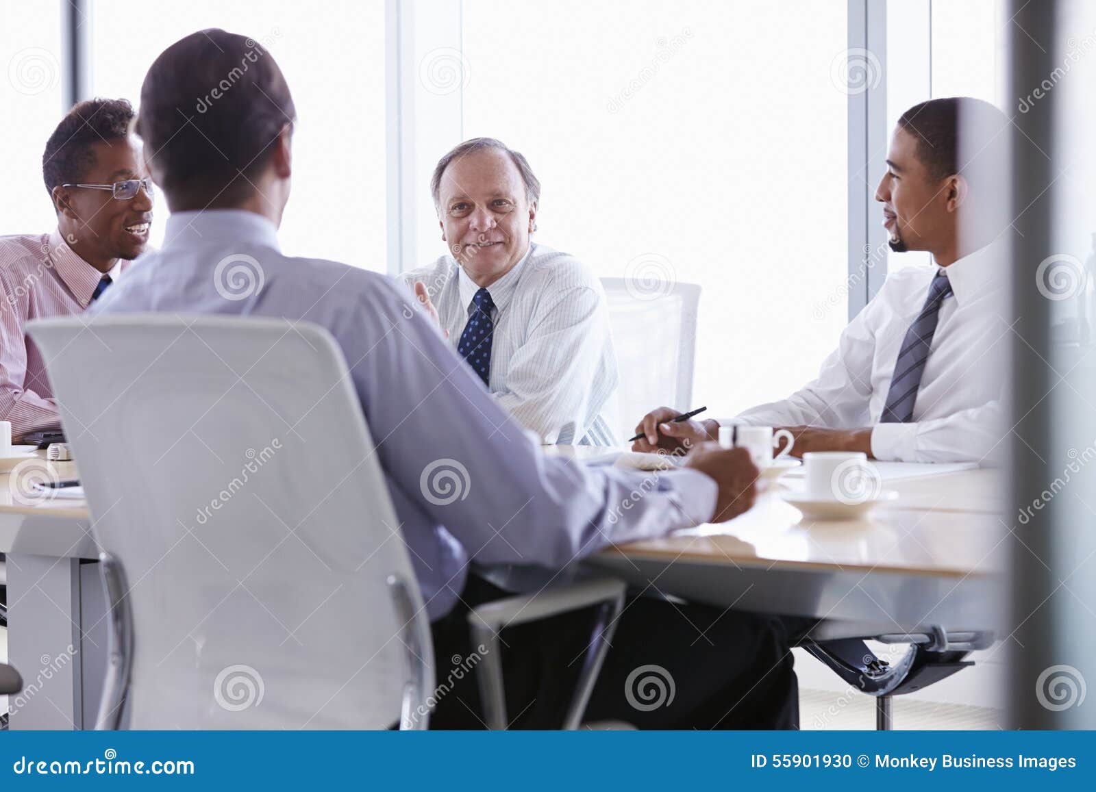 Four Businessmen Having Meeting Around Boardroom Table Stock Photo ...