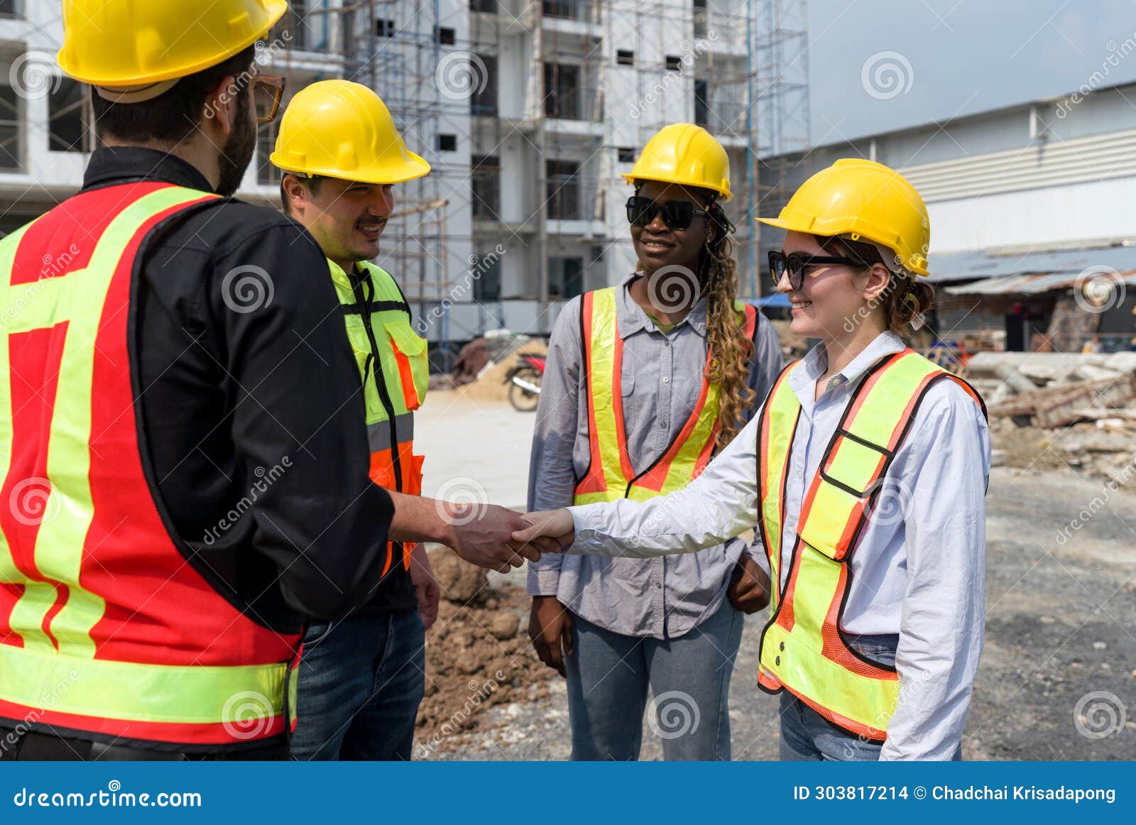 Four Construction Workers Celebrating with a Handshake in Front of an ...