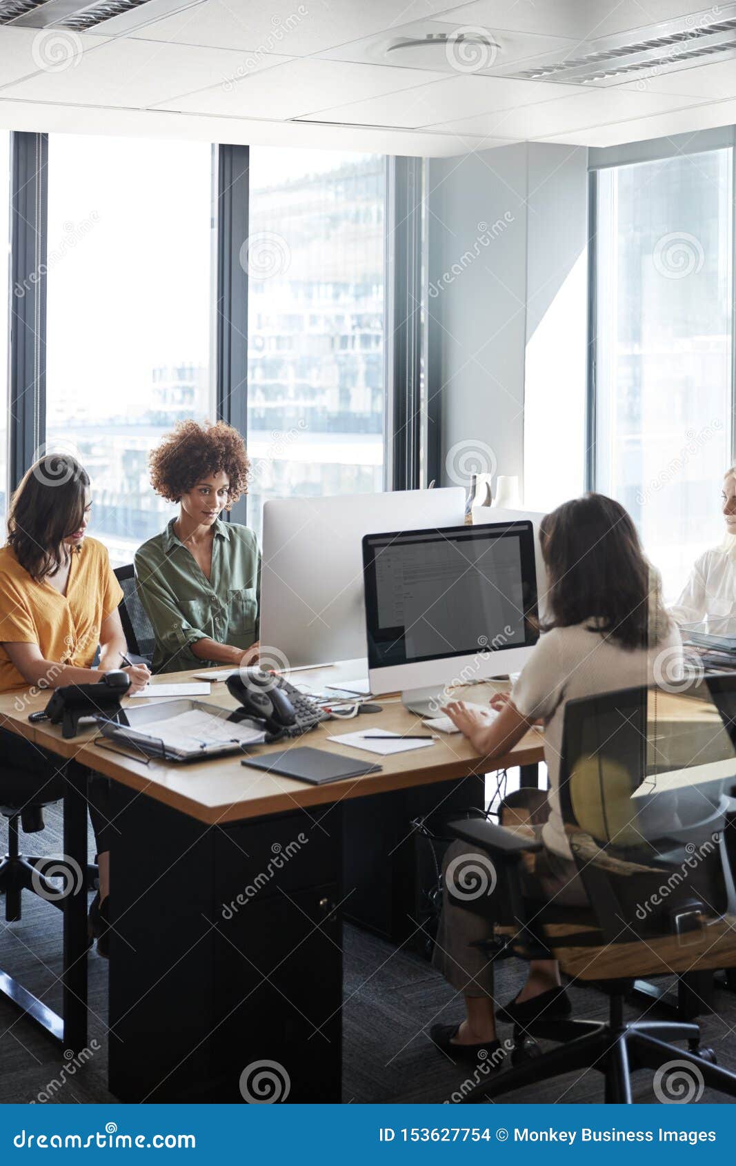 Four Female Creative Colleagues Working Together in an Office, Vertical ...