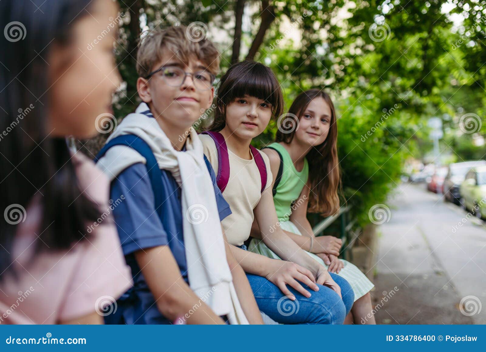 Four Friends Classmates Sitting Outdoors, Waiting for Bus. Stock Photo ...