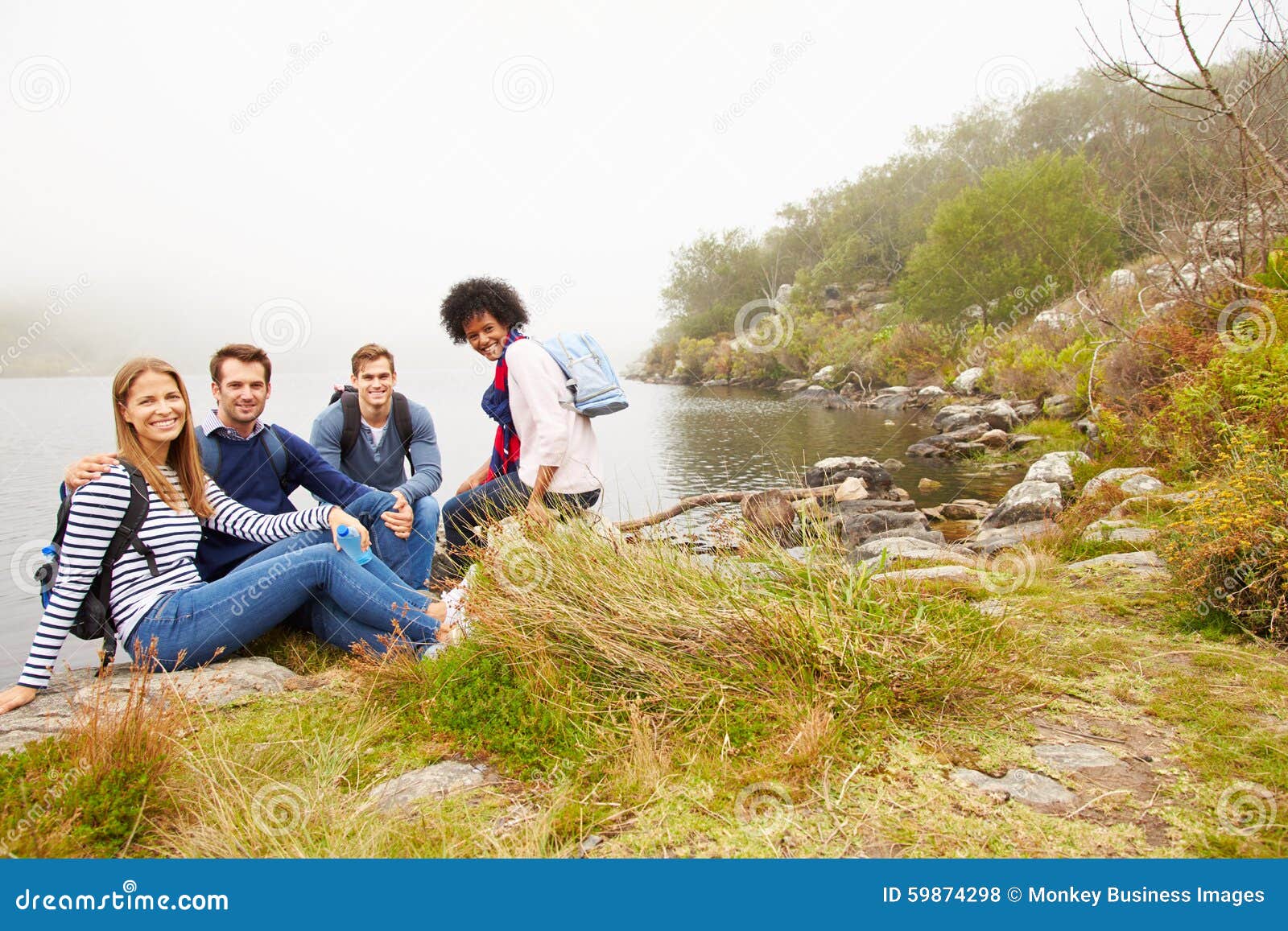 Four Friends Relaxing by the Edge of a Lake Stock Photo - Image of ...