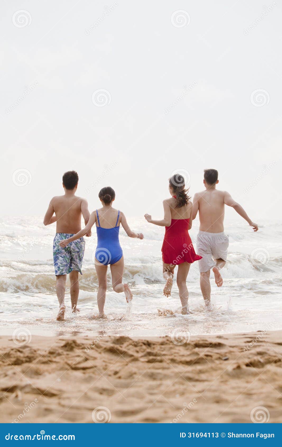 Four Friends Running into the Water on a Sandy Beach Stock Image ...