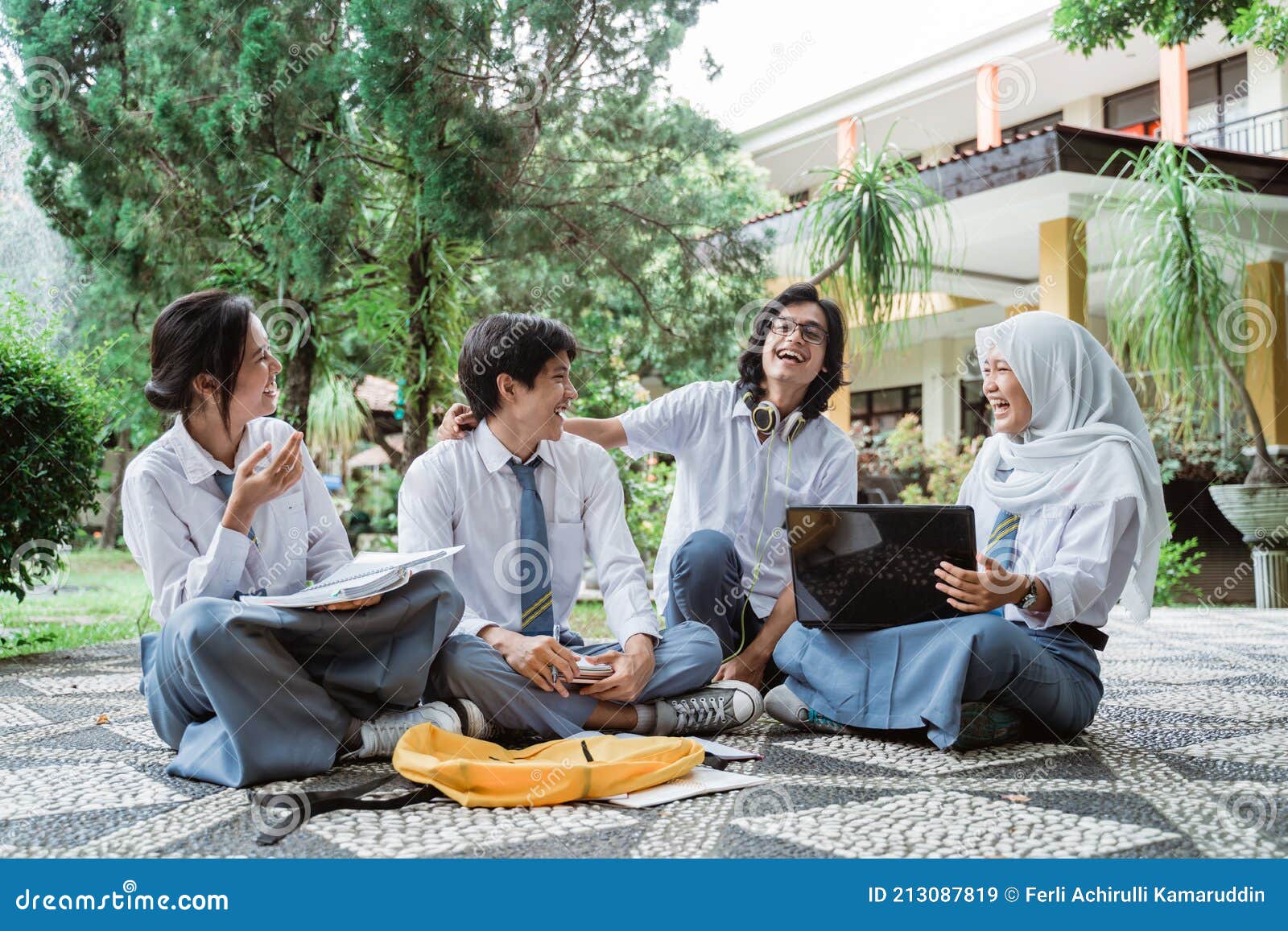 Four High School Students Smile while Chatting and Use Laptops during ...