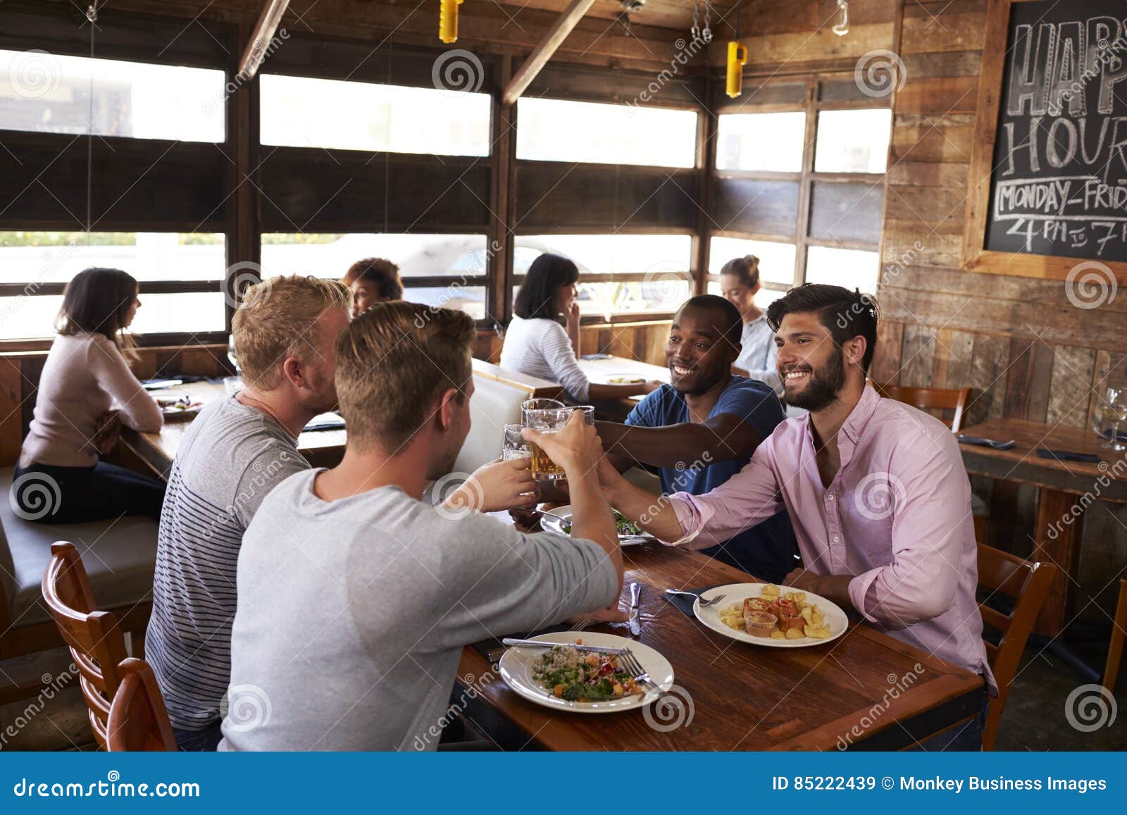 Four Male Friends Making a Toast at a Table in a Restaurant Stock Image ...