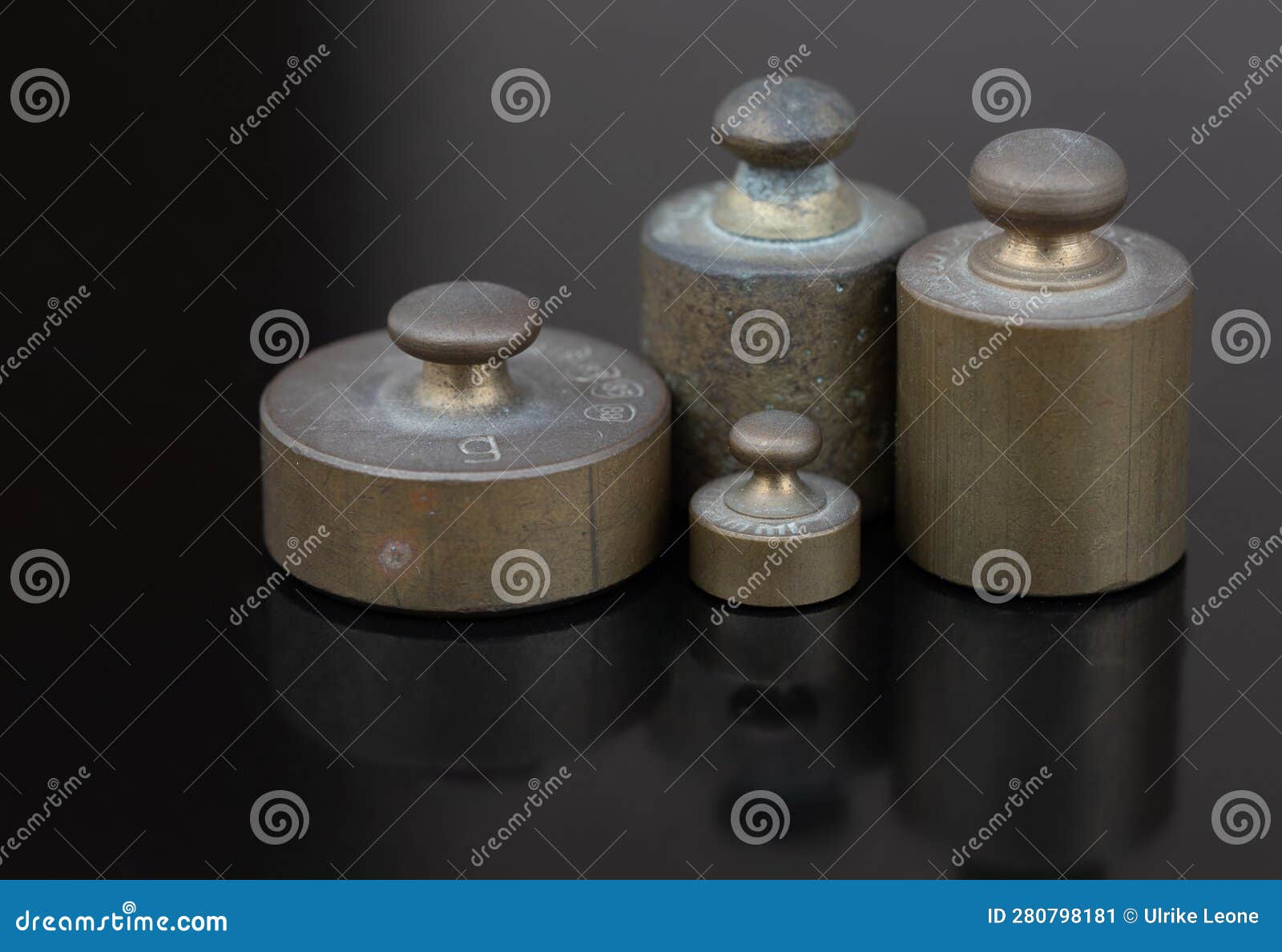 Four Metal Weights Stand Next To Each Other in Front of a Dark ...