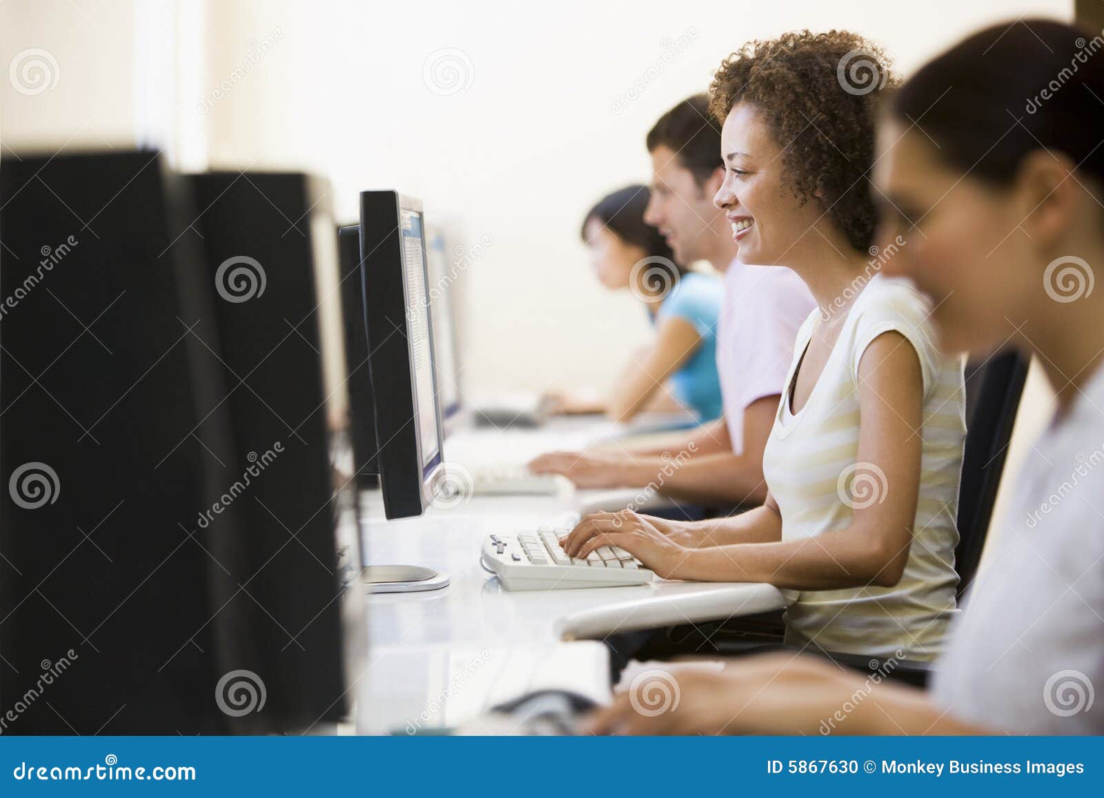 Four People in Computer Room Typing and Smiling Stock Photo - Image of ...