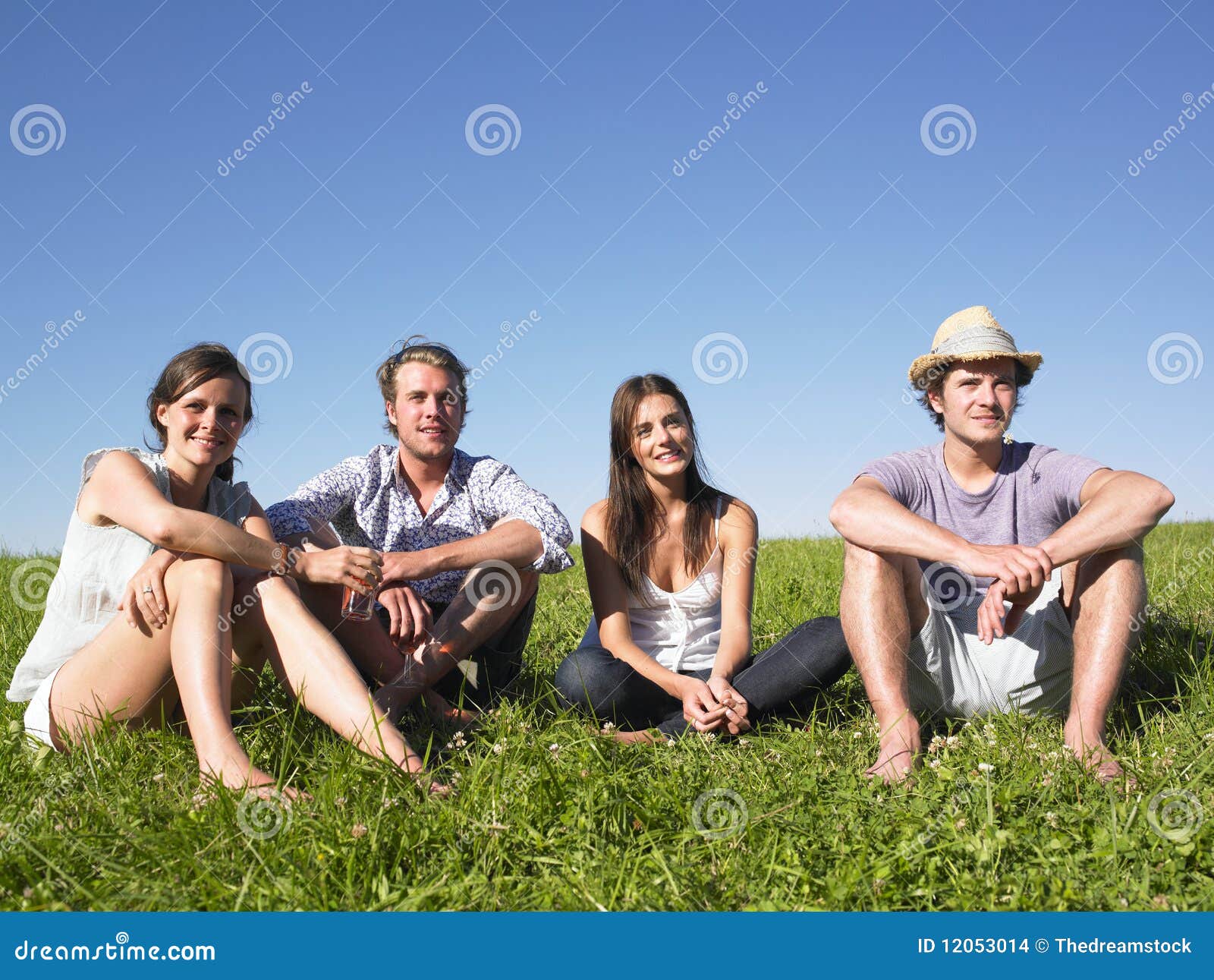 Four People Sitting on the Grass Stock Photo - Image of outdoors, blond ...