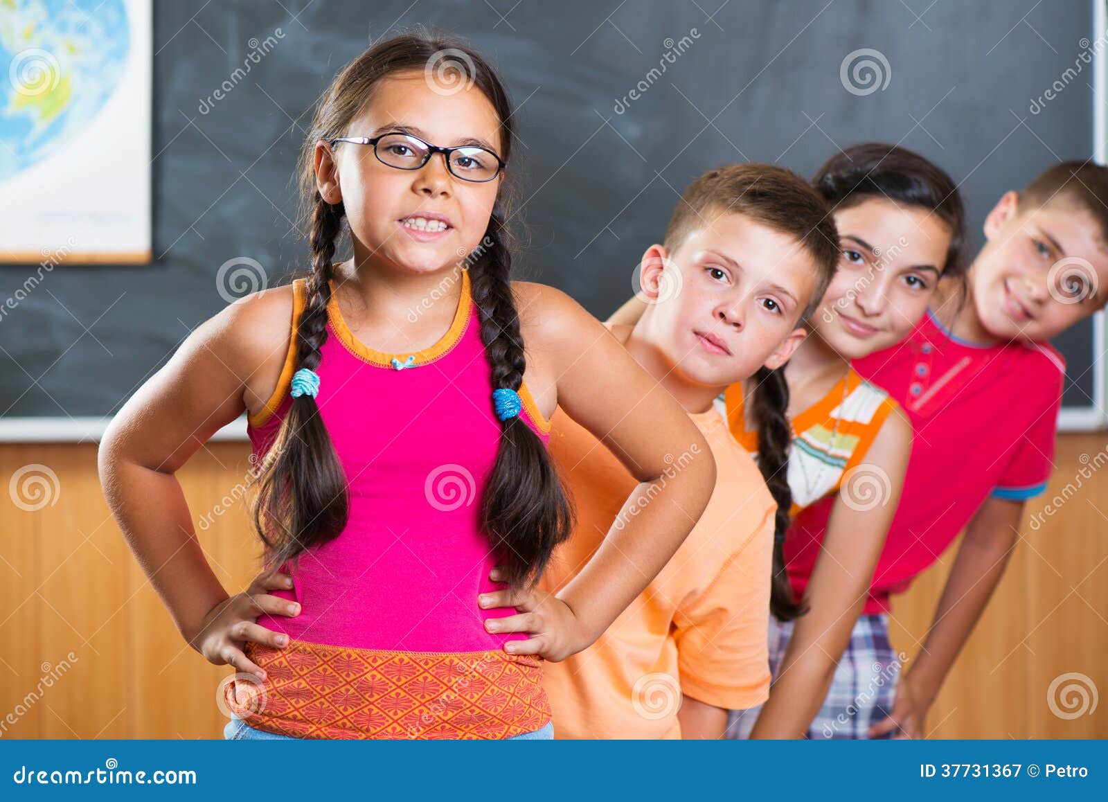 Four Schoolchildren Standing in Classroom Against Blackboard Stock ...