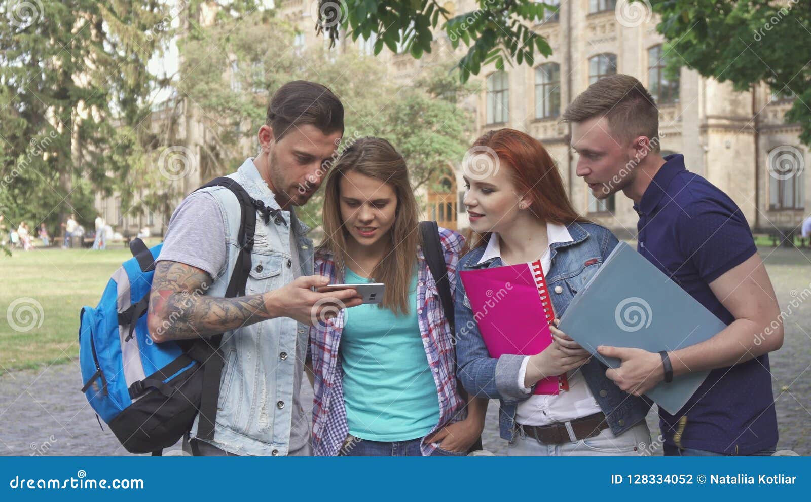 Four Students Look at Smartphone Screen on Campus Stock Photo - Image ...
