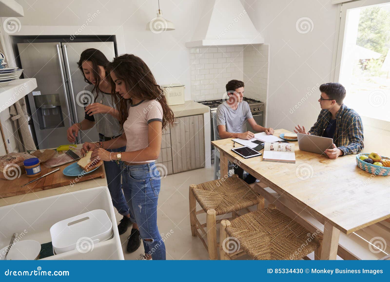 Four Teenagers Making Lunch and Studying Together in Kitchen Stock ...