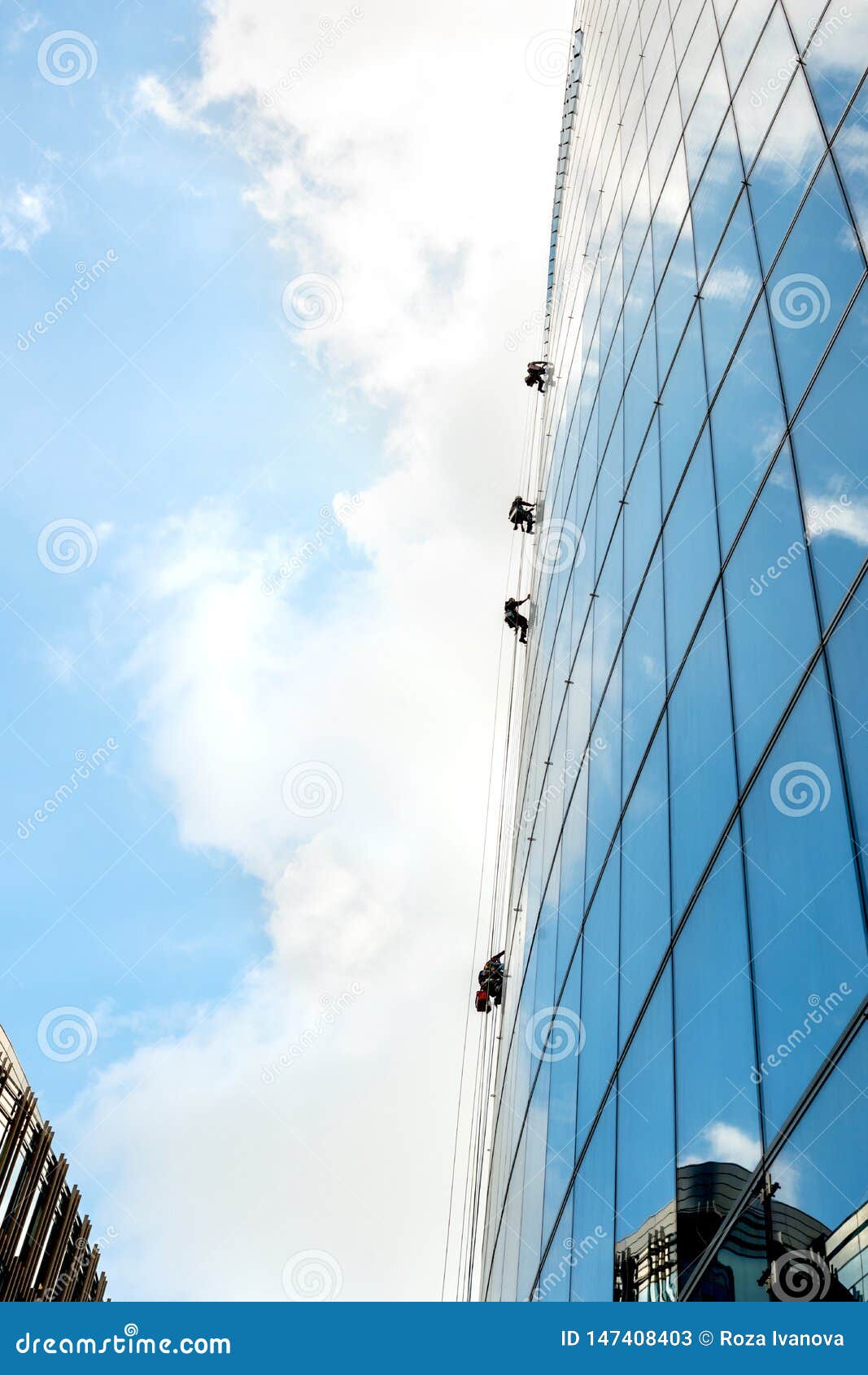 Four Window Washers Work at a Height on a High-rise Building with a ...
