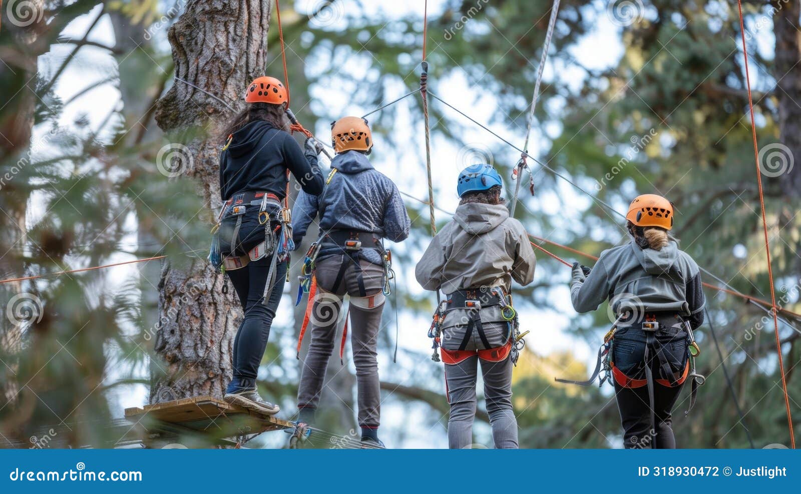 Four Workers Wearing Harnesses and Guiding Each Other on a High Ropes ...
