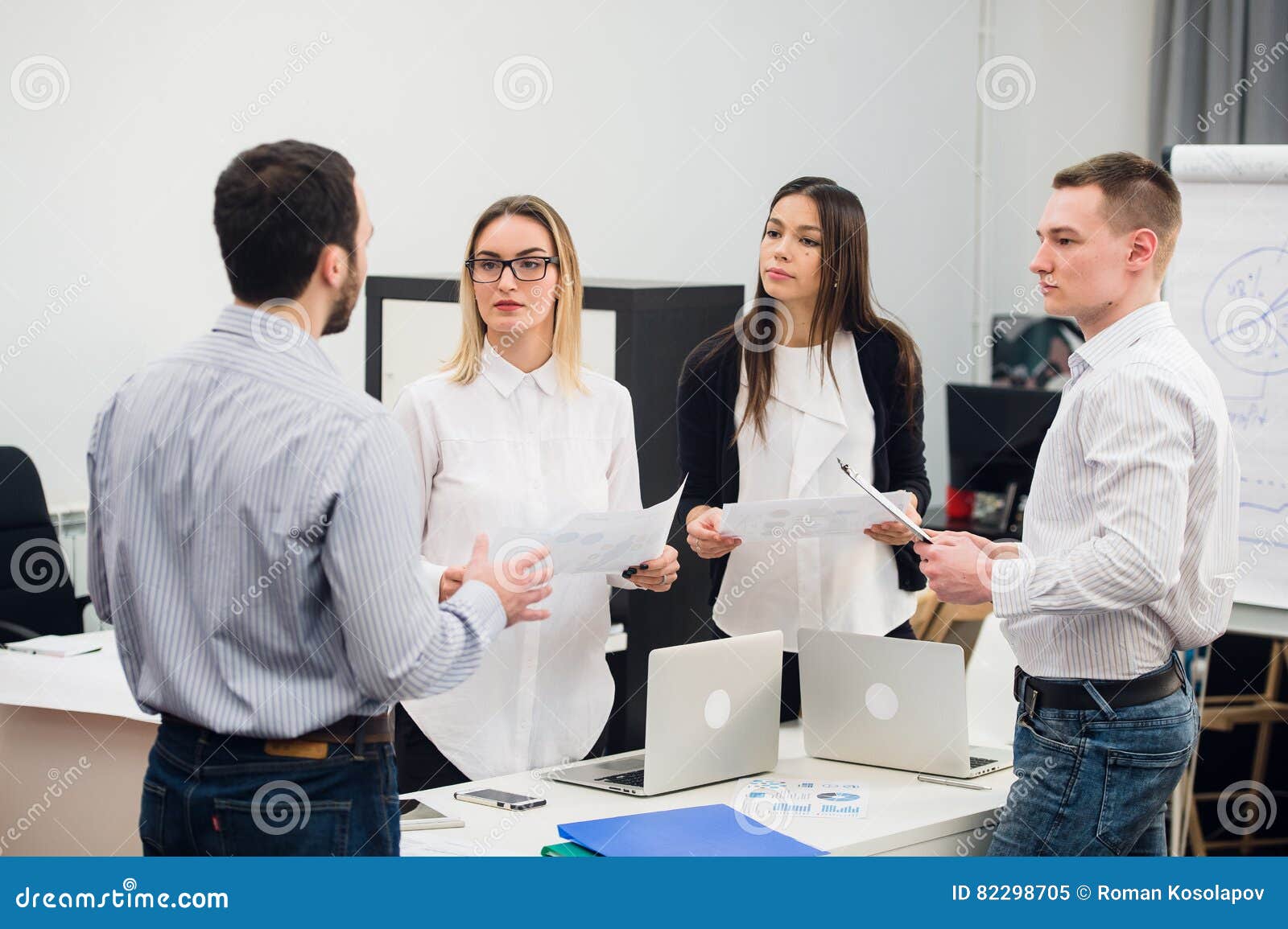 Four Young Business People Working As a Team Gathered Around Laptop ...