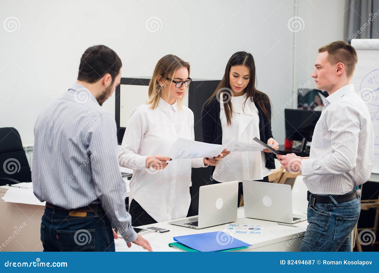 Four Young Business People Working As a Team Gathered Around Laptop ...