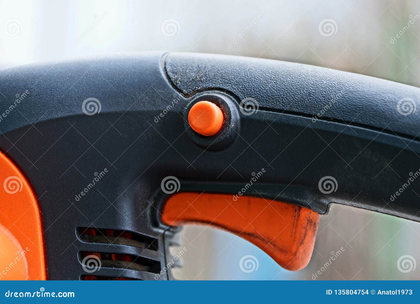 Part of a Power Tool with an Orange Button and a Trigger on a Black ...