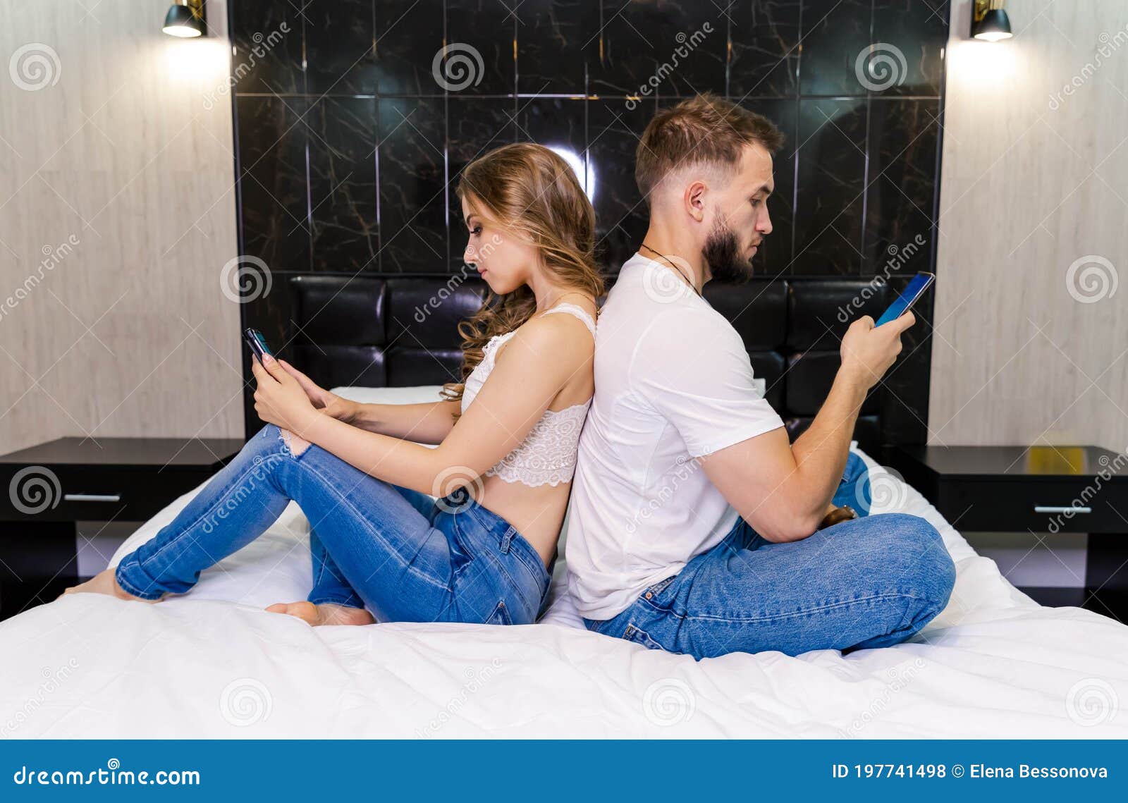 Man And Woman Sitting Back To Back On Bed In Bedroom Together Stock