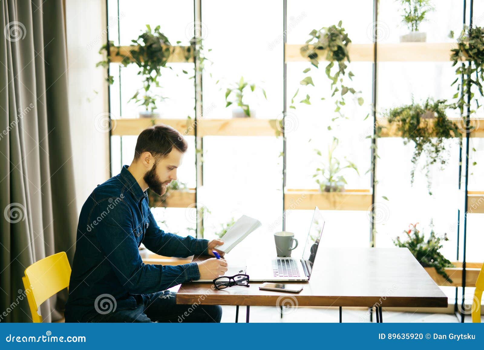 Freelance Man Working on Line with a Laptop and Holding Documents in a ...