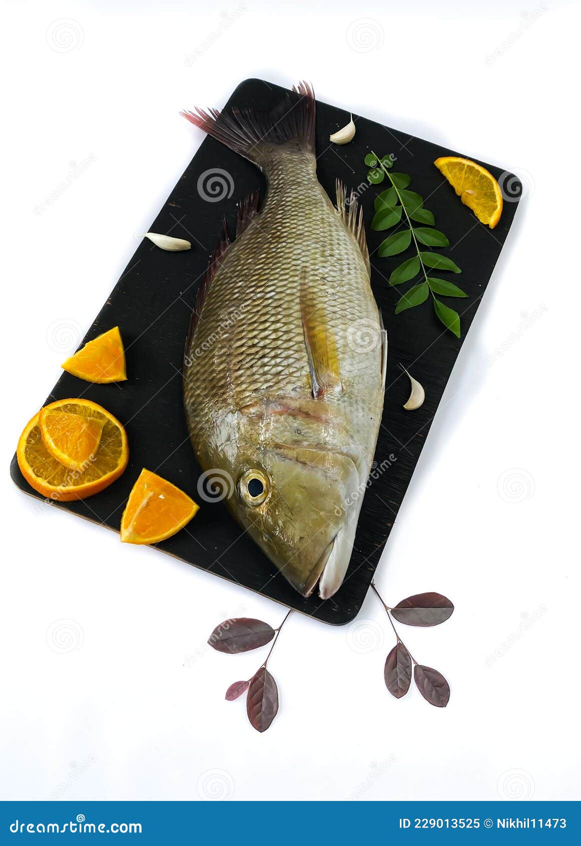 Fresh Emperor Fish Decorated with Herbs and Vegetables on a Black Pad ...