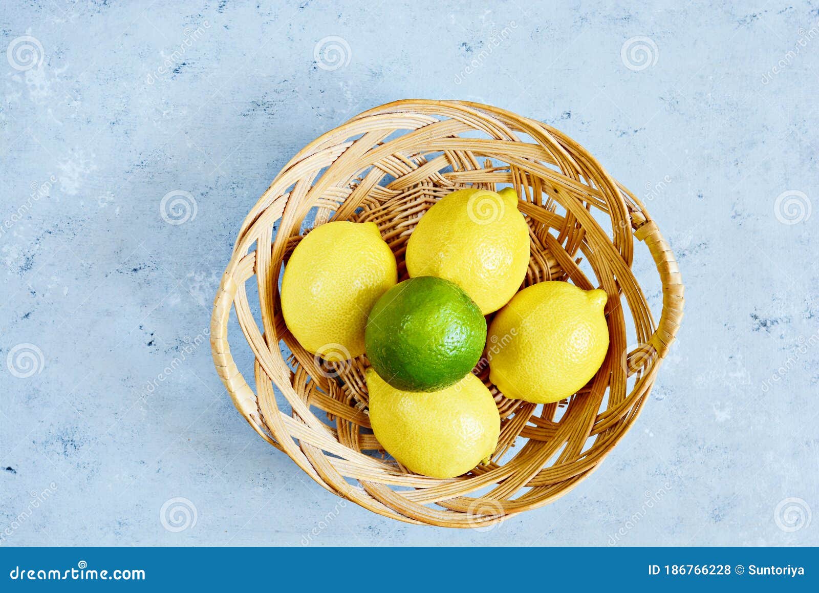 Fresh Lemons and Limes in a Basket on a Blue Background. Stock Photo ...