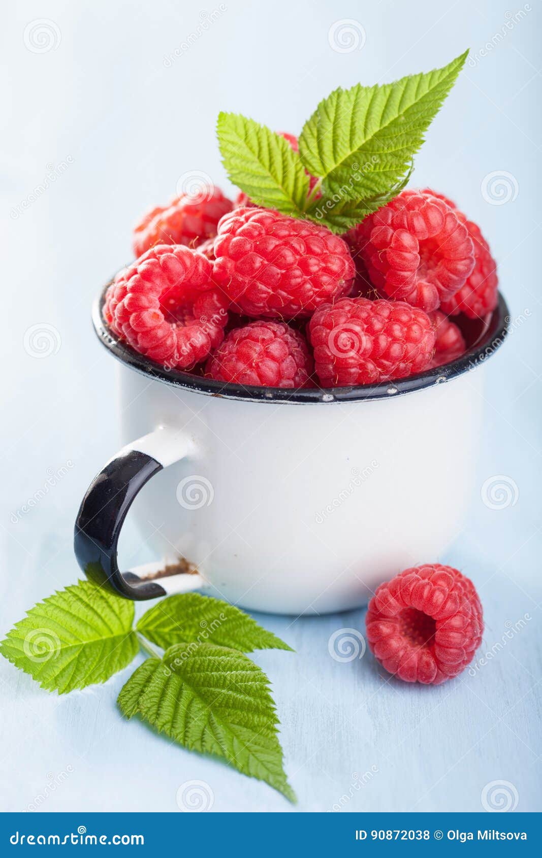 Fresh Raspberry in Enamel Cup Over Blue Background Stock Photo - Image ...