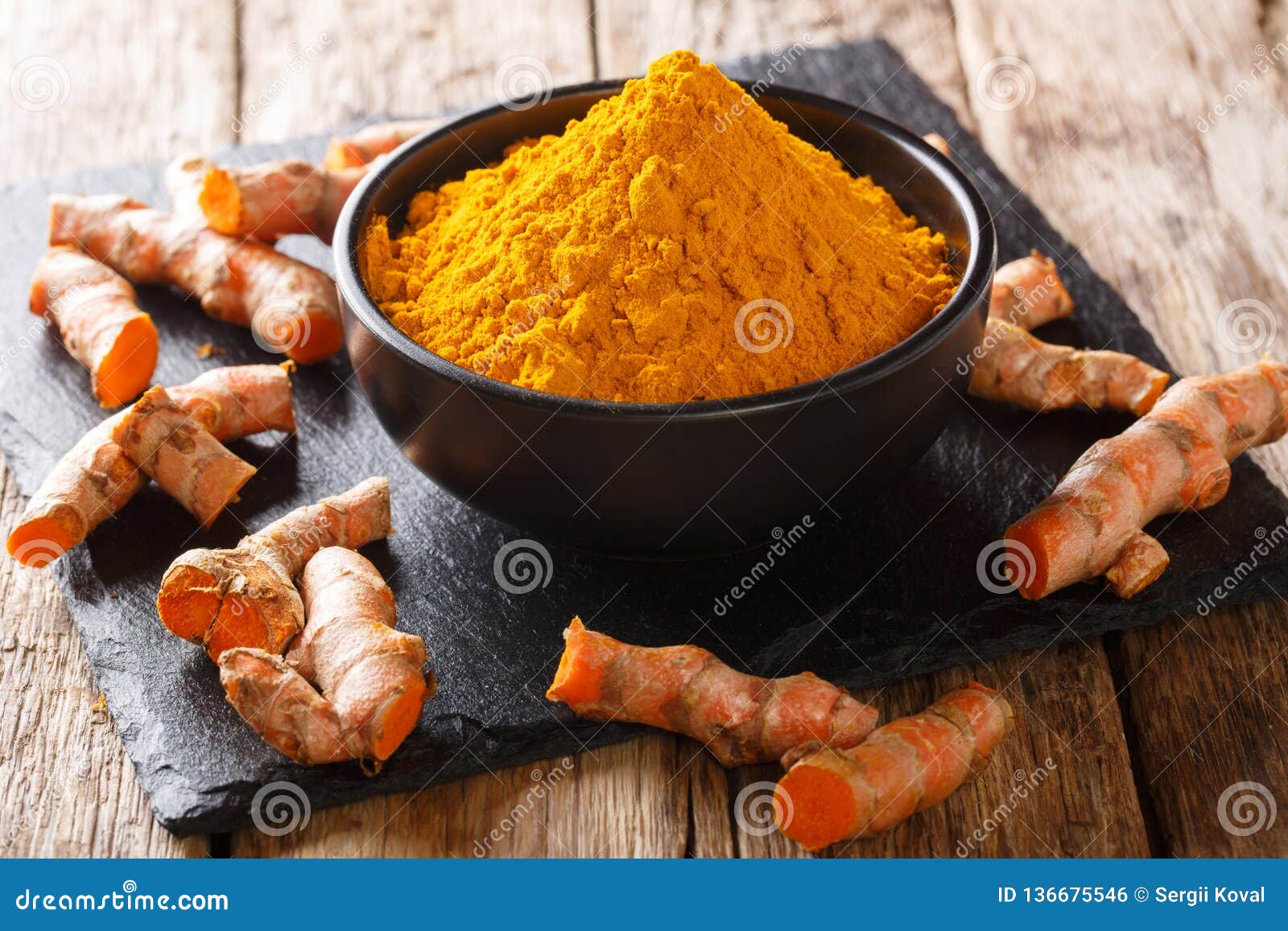 Freshly Ground Turmeric in a Black Bowl and Fresh Root Close-up ...
