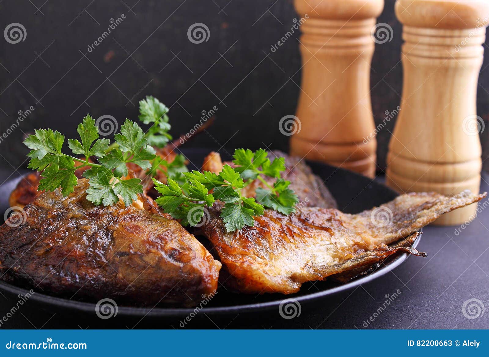 Fried Fish on a Black Plate Decorated with Fresh Parsley Stock Image ...