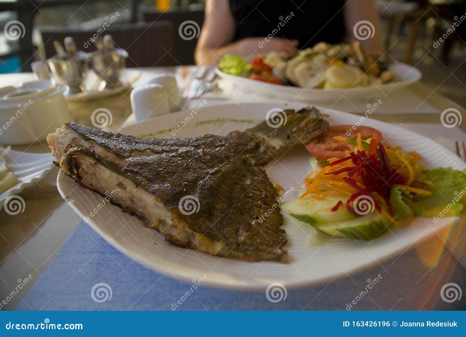 Fried Half of a Large Fish Served on a White Plate with Vegetables in a ...
