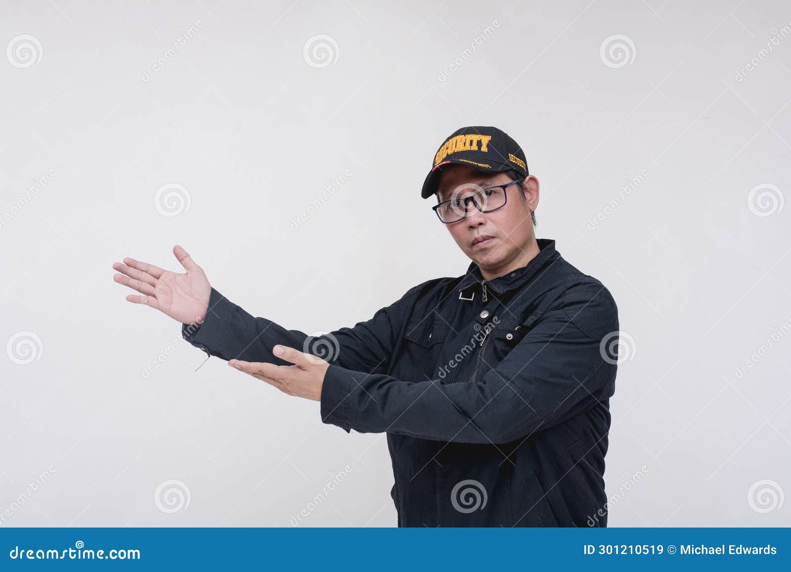 A Friendly Asian Male Security Guard Points To the Left with Both Hands ...
