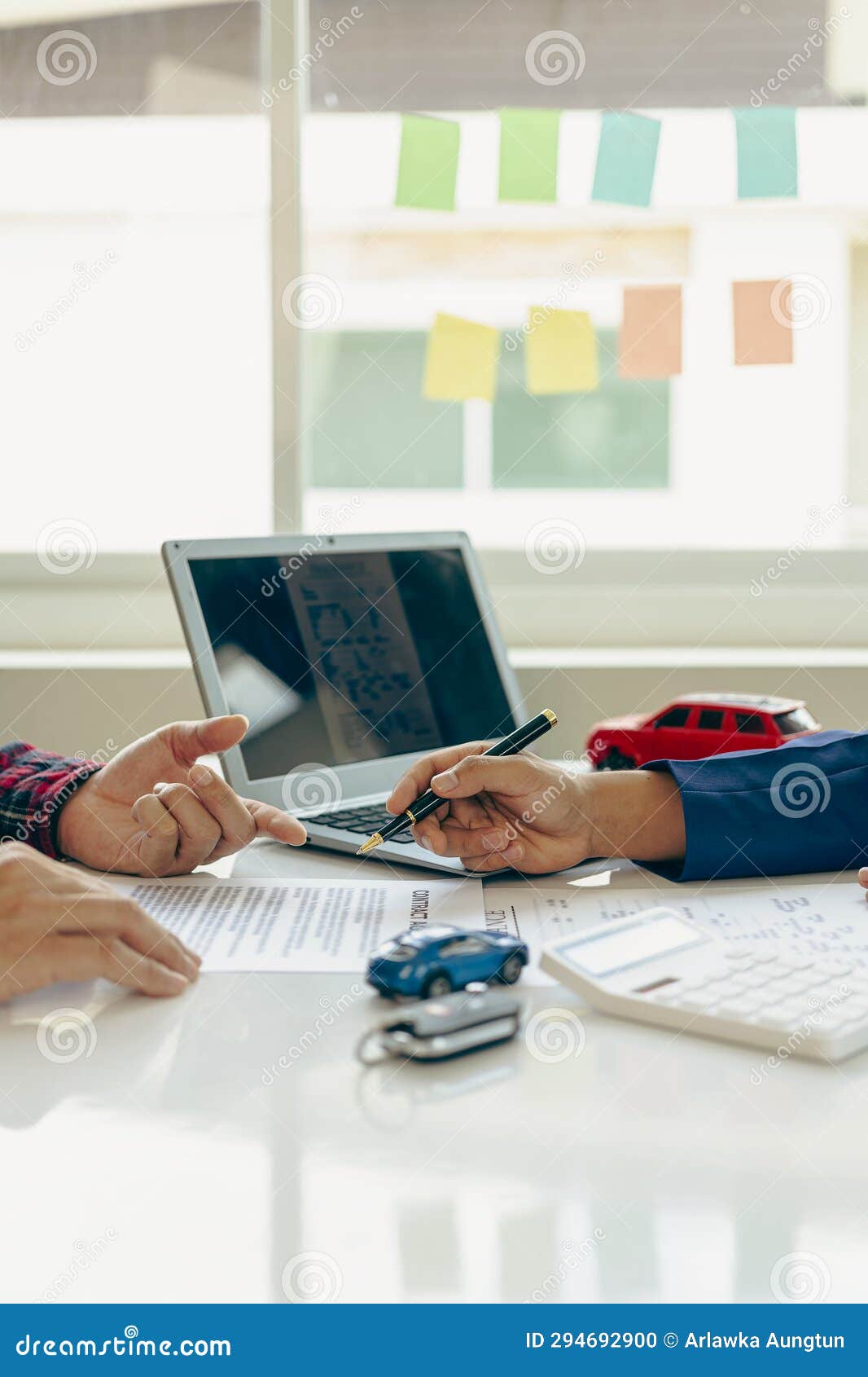 A Friendly Car Salesman is Sitting at a Table with a Customer. and ...